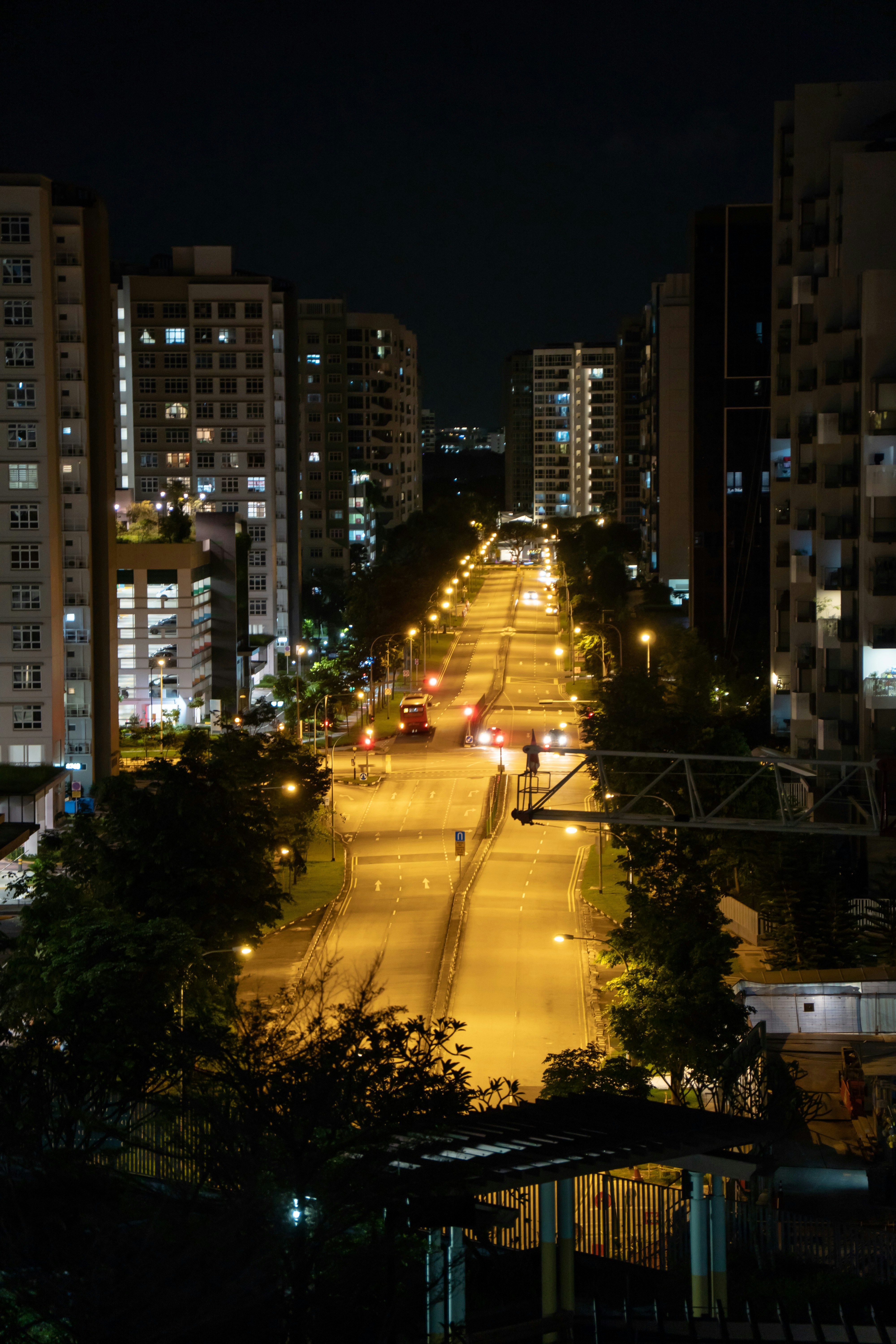 Illuminated street winding through high-rise buildings at night, showcasing a blend of urban life and architecture.
