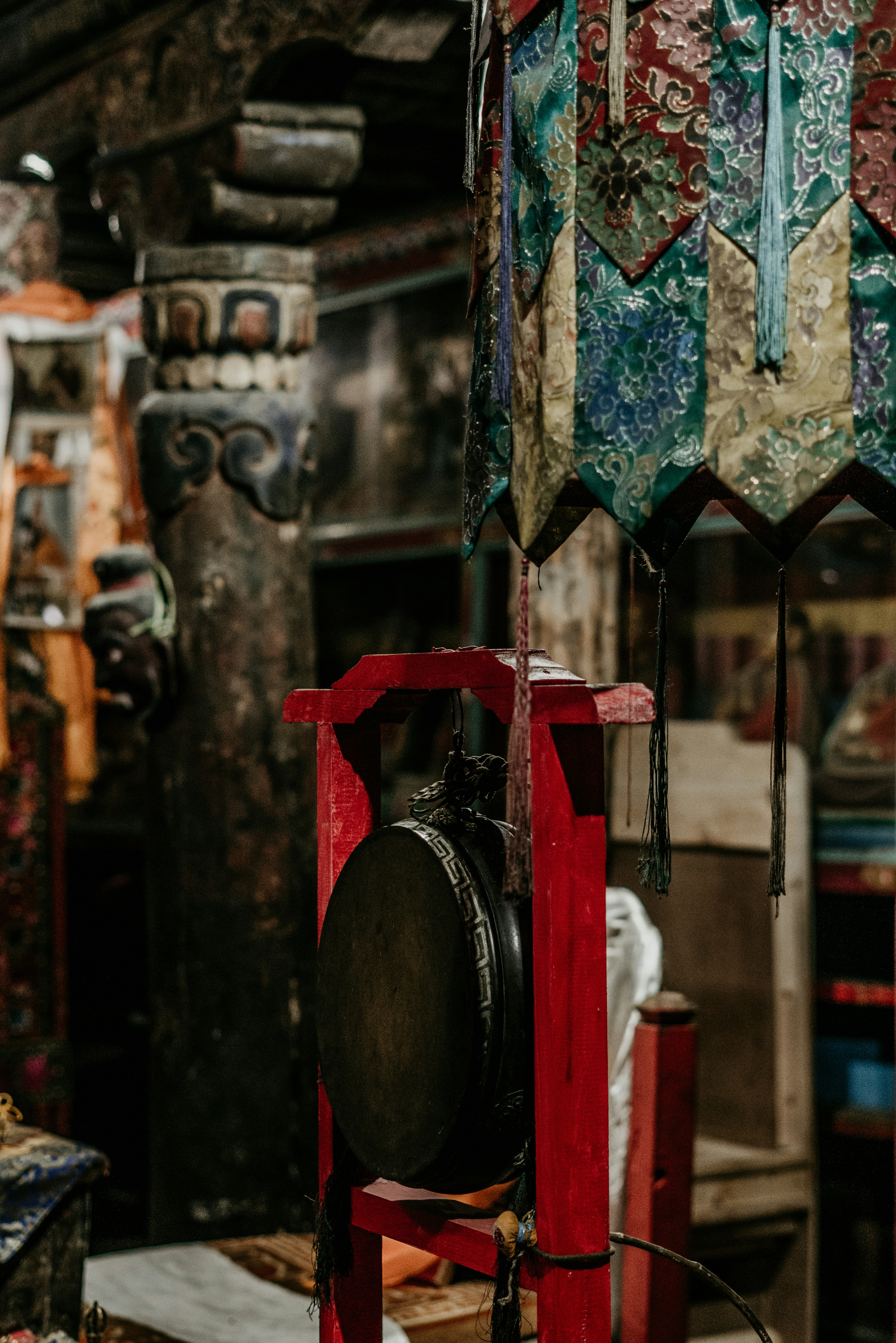 Red Gong Framed by Velvet Banners in a Dim Tibetan Shrine