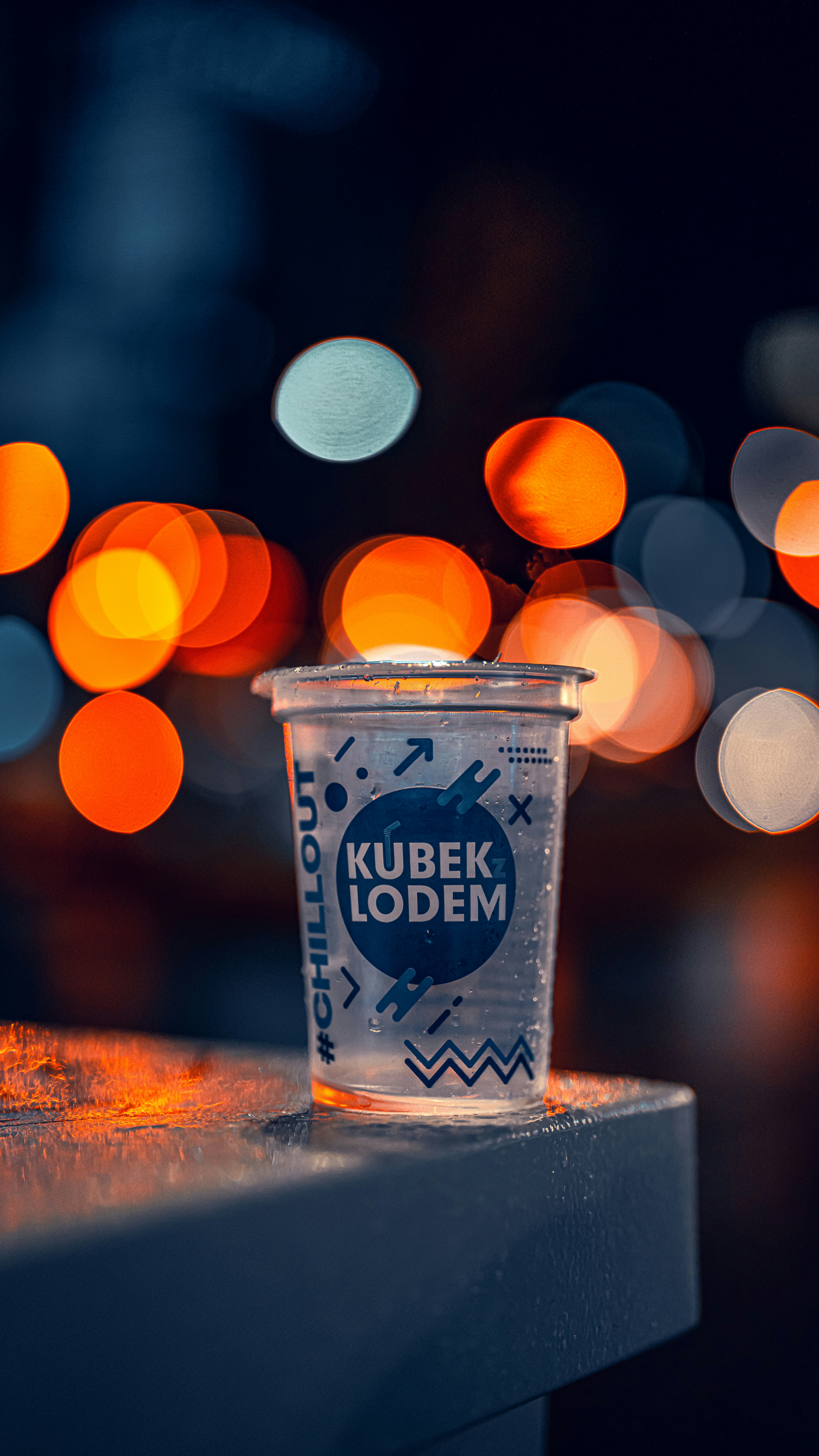 Neon Orbs Behind a Lone Cup on a Night Rail
