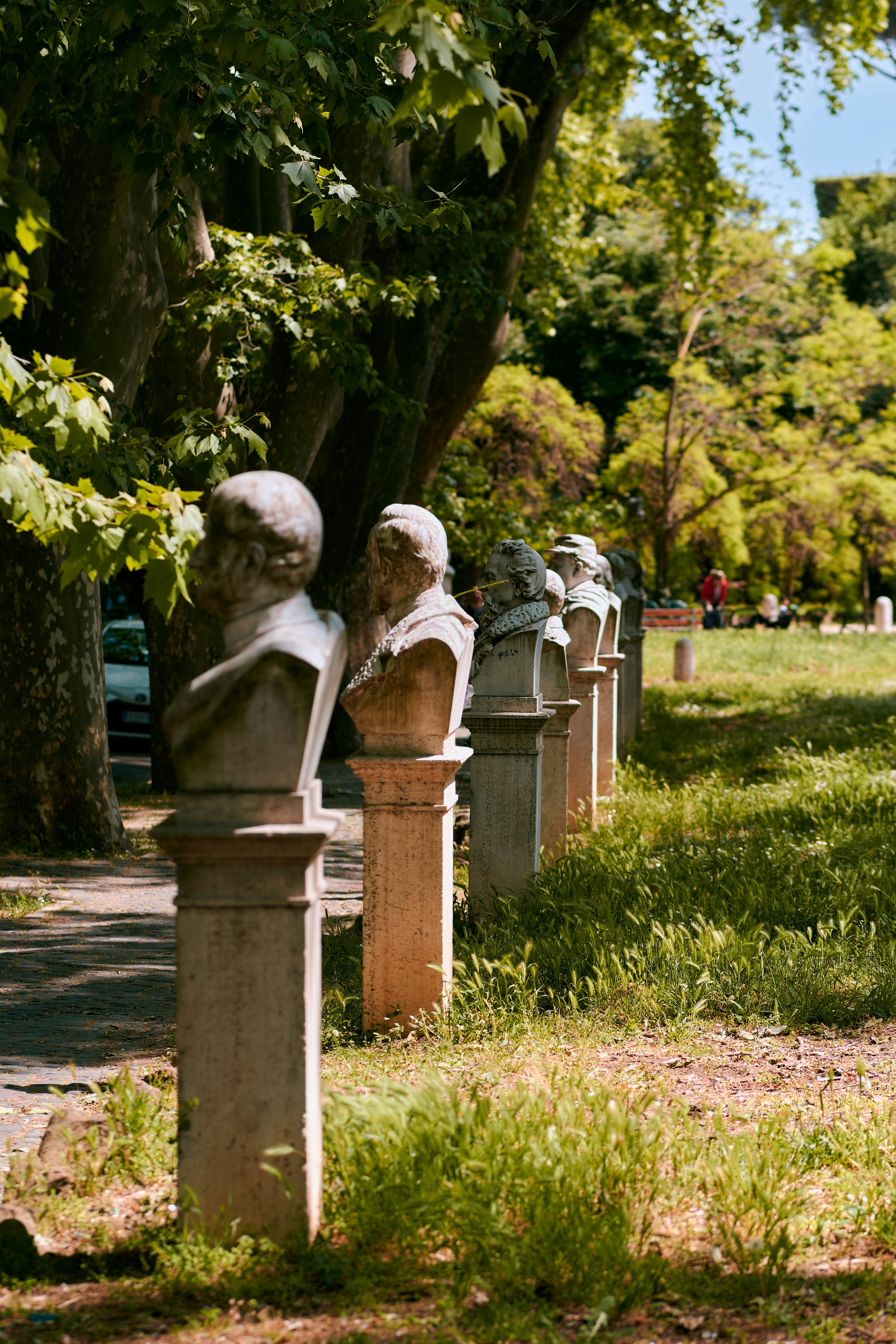 A row of statues sitting on top of a lush green park photo – Free Italy ...