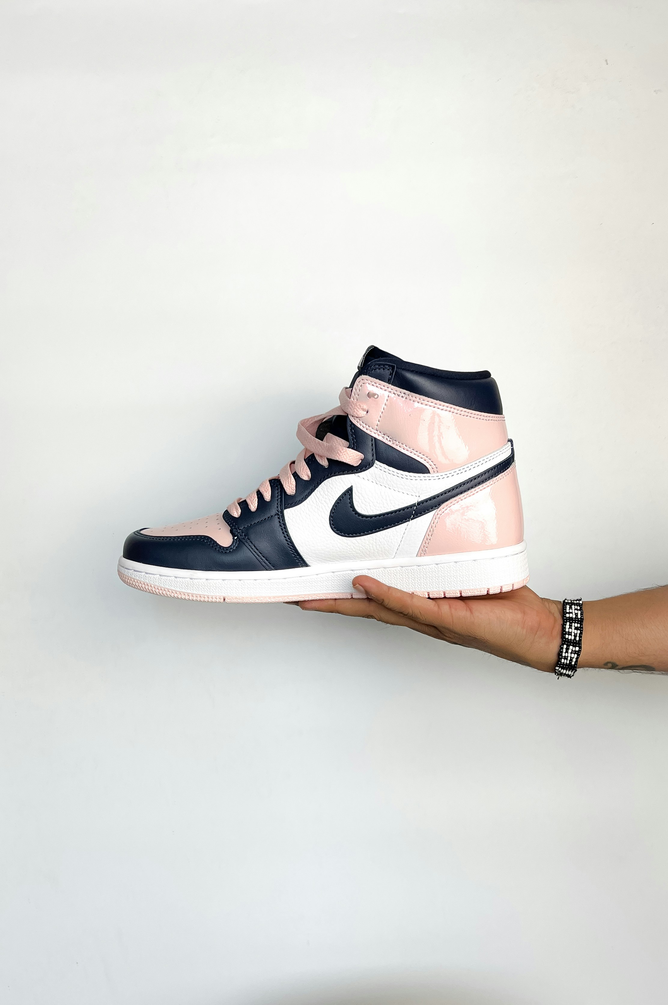 A Delicate Balance: Pink-Nav y Nike Mid-Top Hovering on a Gentle Palm