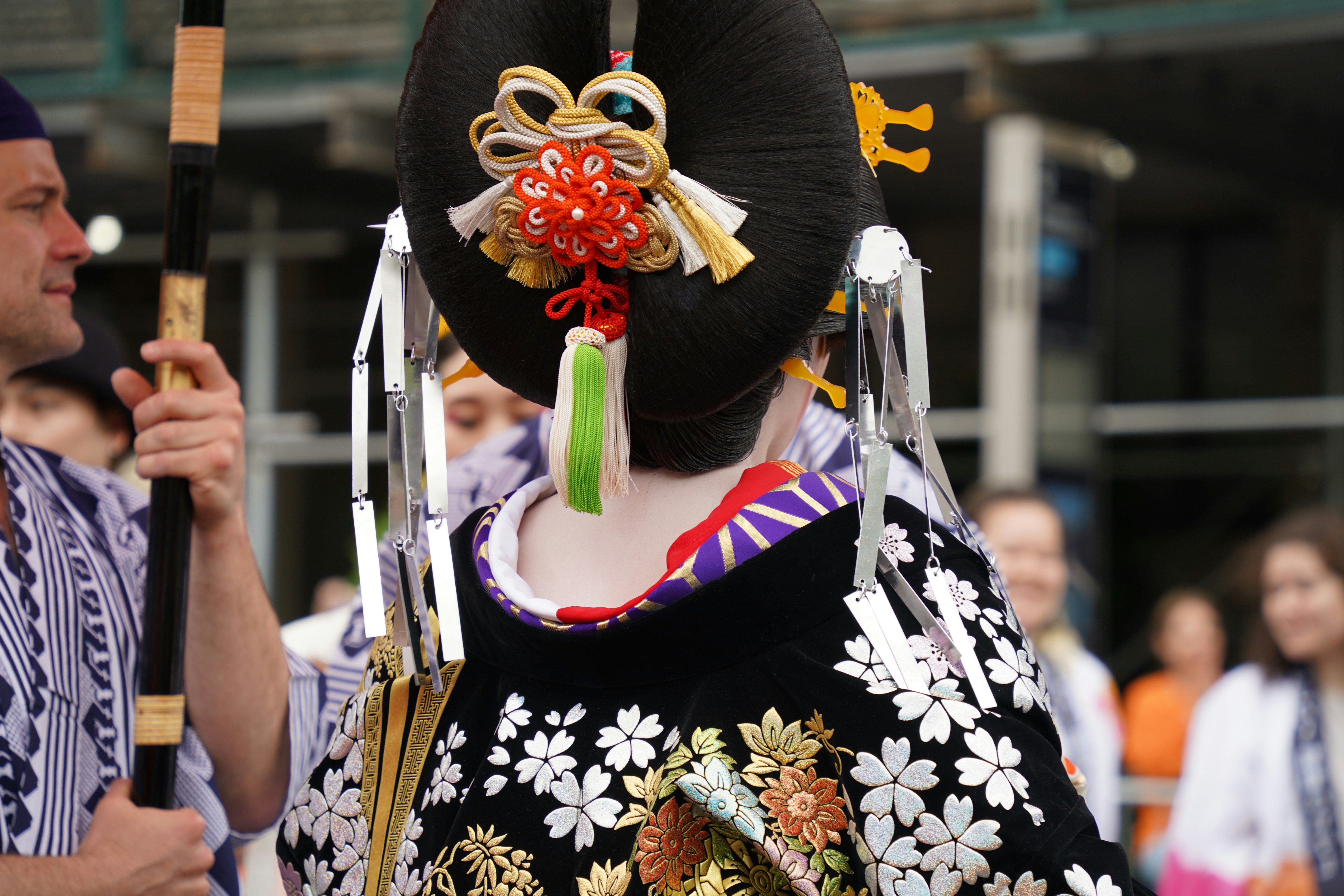 Traditional Japanese attire adorned with intricate floral patterns, showcasing a graceful hairstyle during a lively festival.