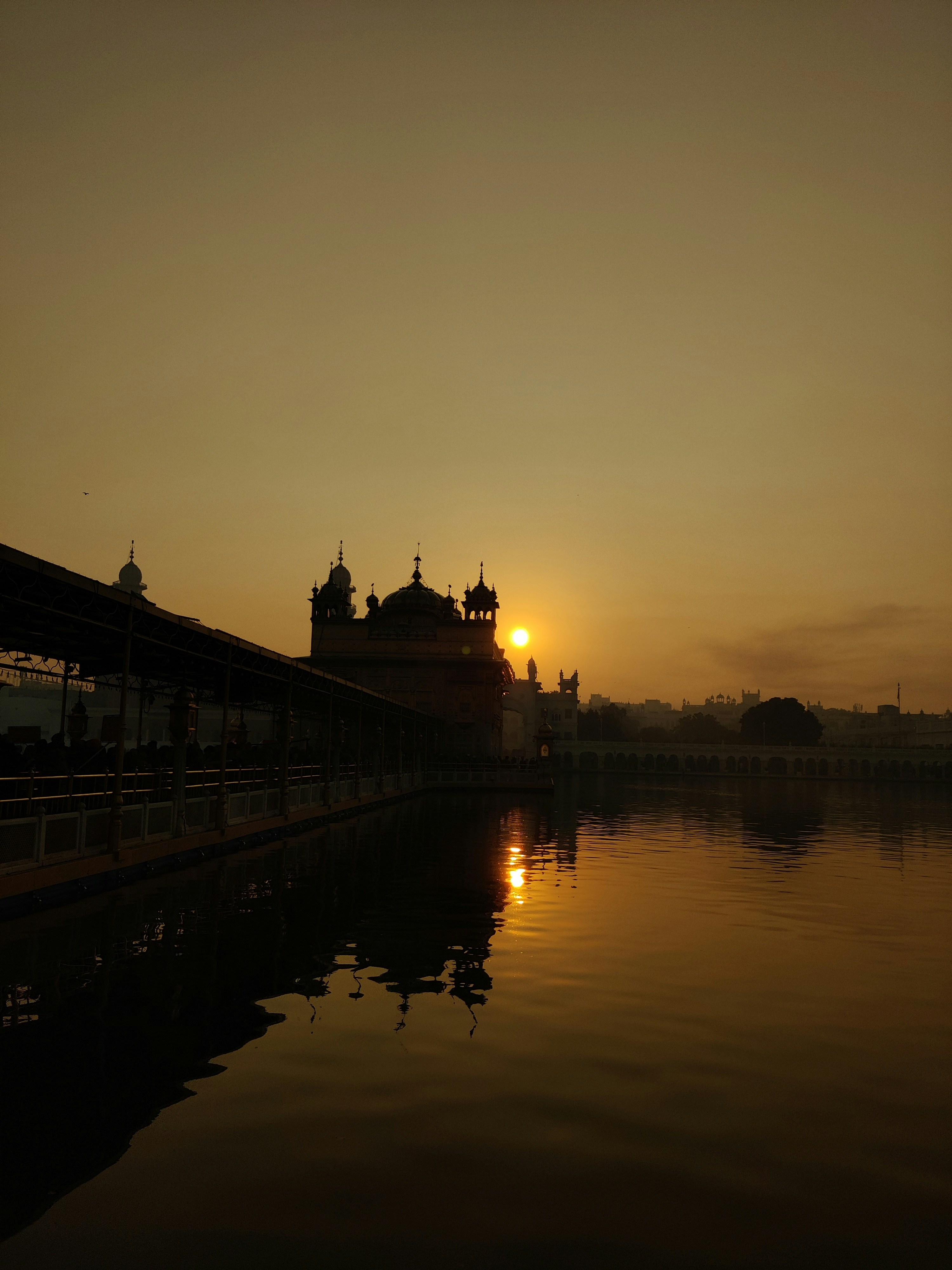 Silhouetted temple reflected in calm waters against a golden sunrise.