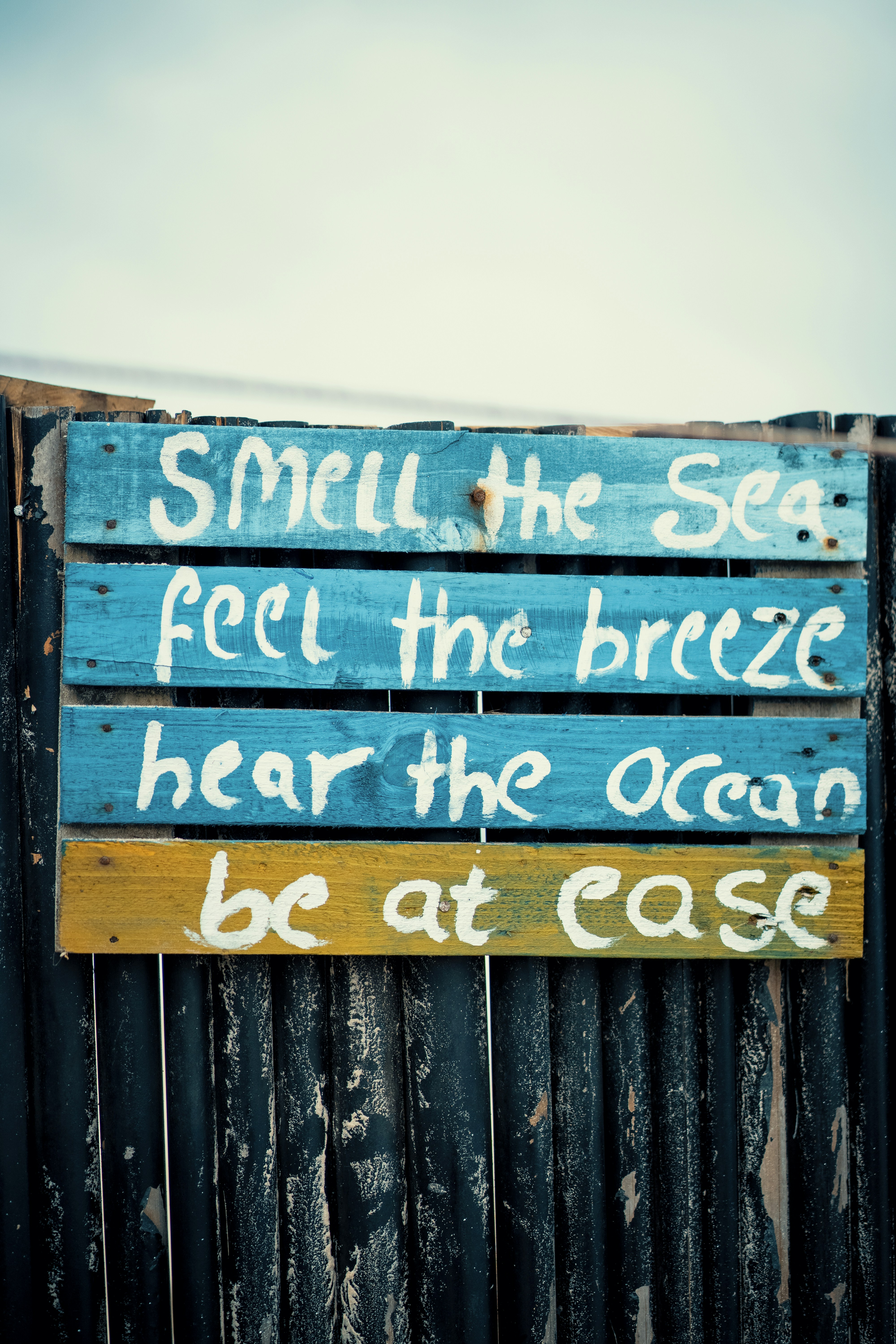 A wooden sign that says smell the sea feel the breeze hear the ocean be ...