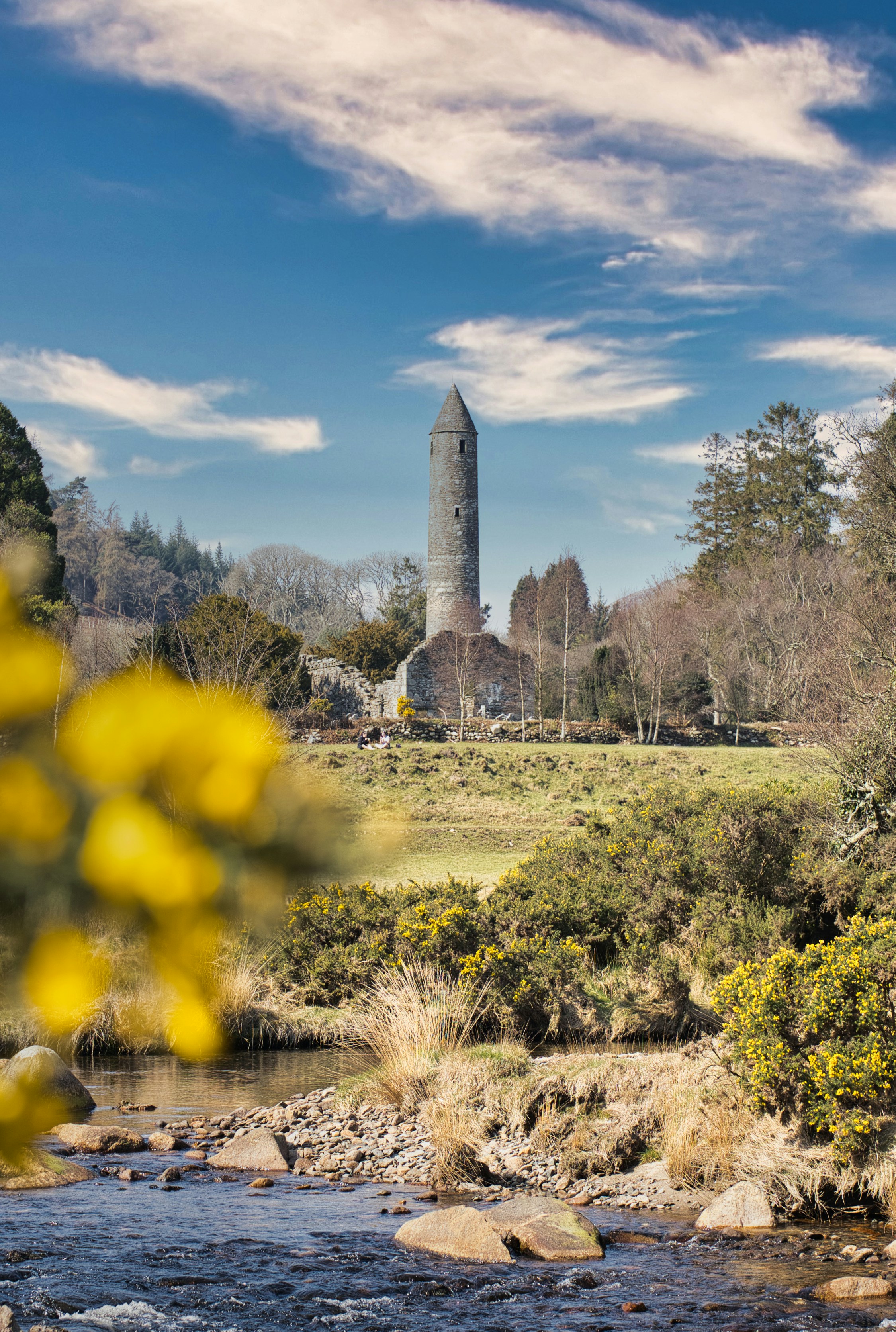 Sentinel by the Stream: A Tall Stone Tower Framed by Spring Light