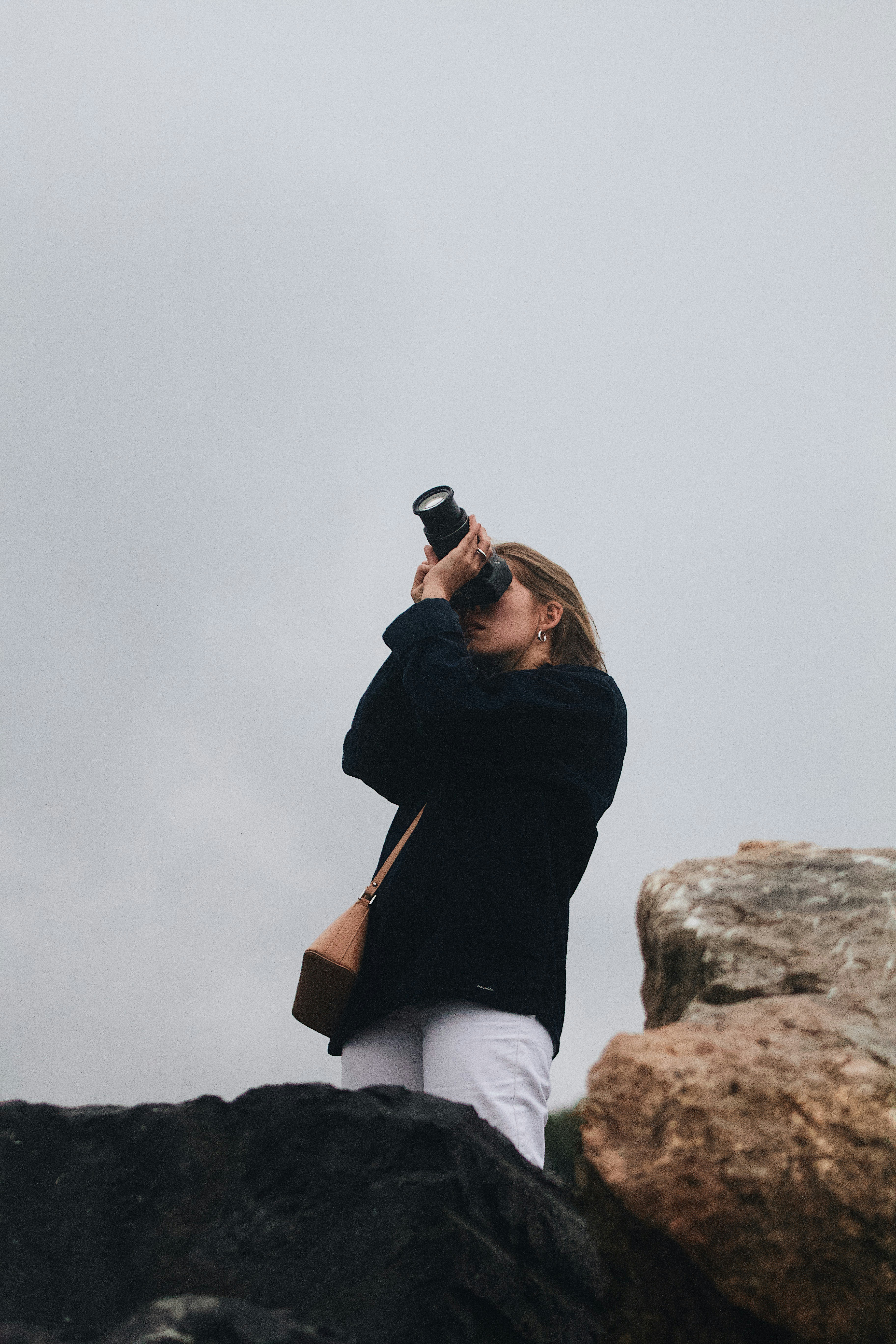 Cliffside Focus: A Photographer on the Edge Aiming Skyward