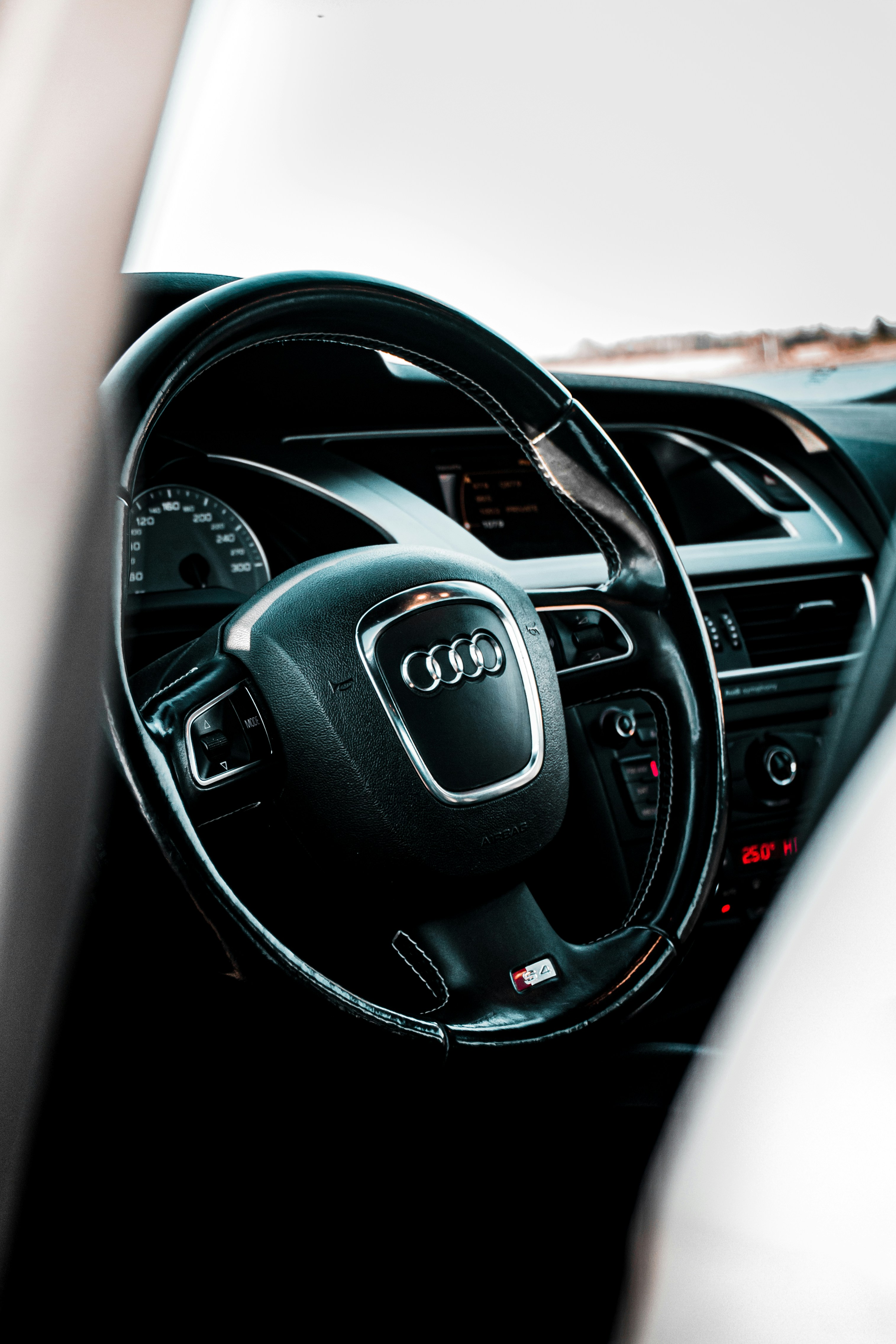 Emblem in Focus: Close-Up of an Audi Steering Wheel Framed by Dashboard Glow