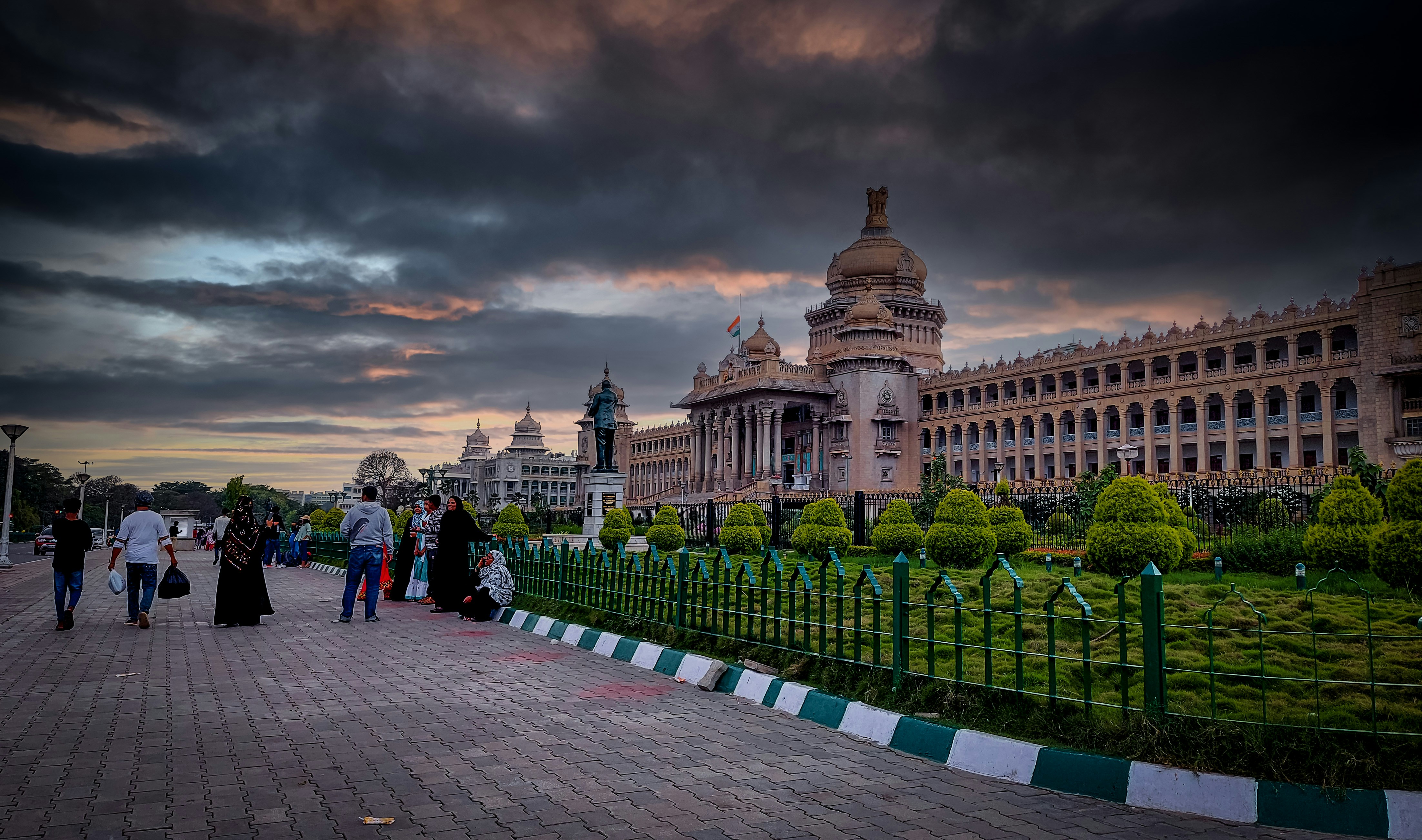 A group of people walking down a sidewalk near a building photo – Free ...