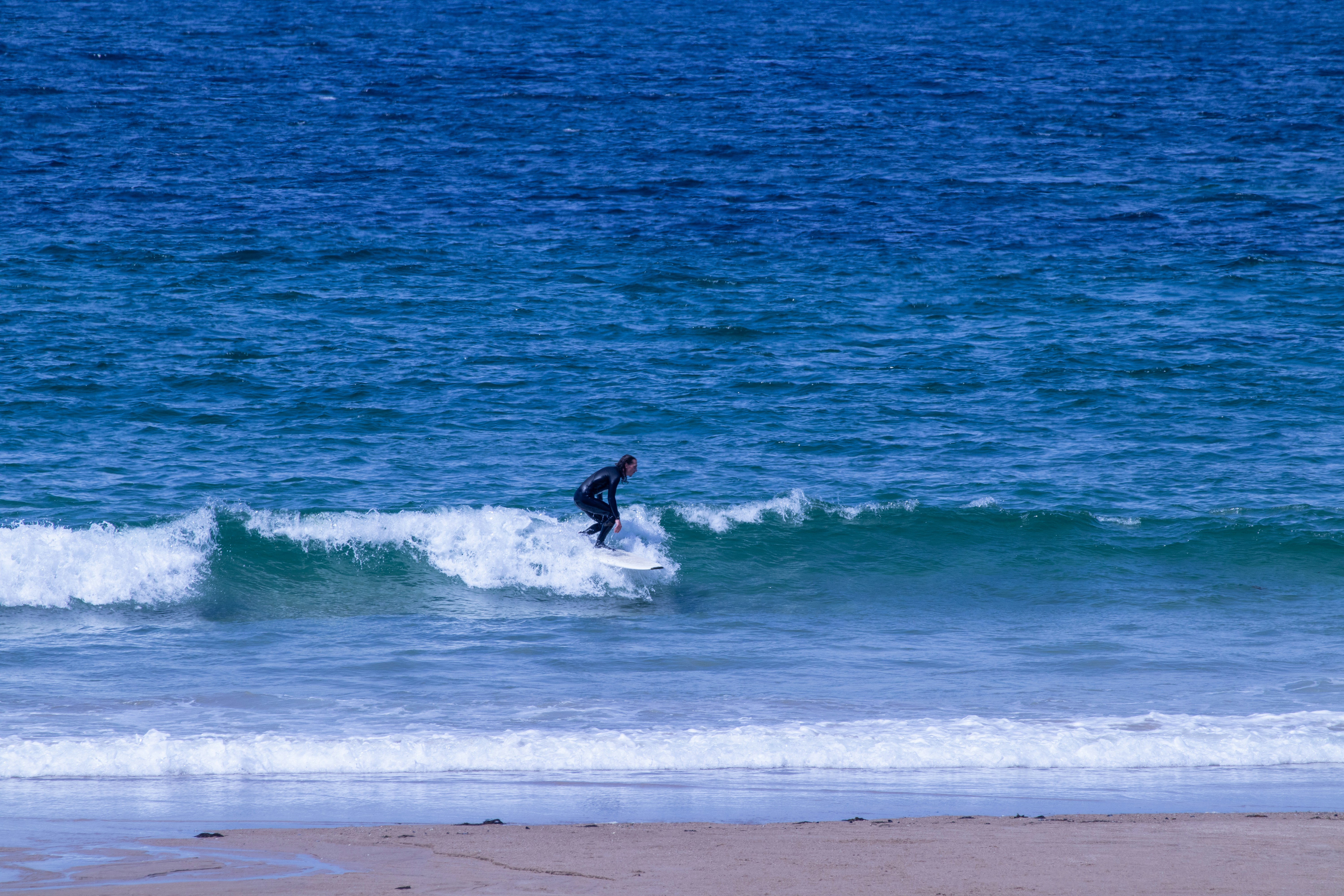 Teal Crest Rider: Solo Surfer on a Quiet Shorebreak