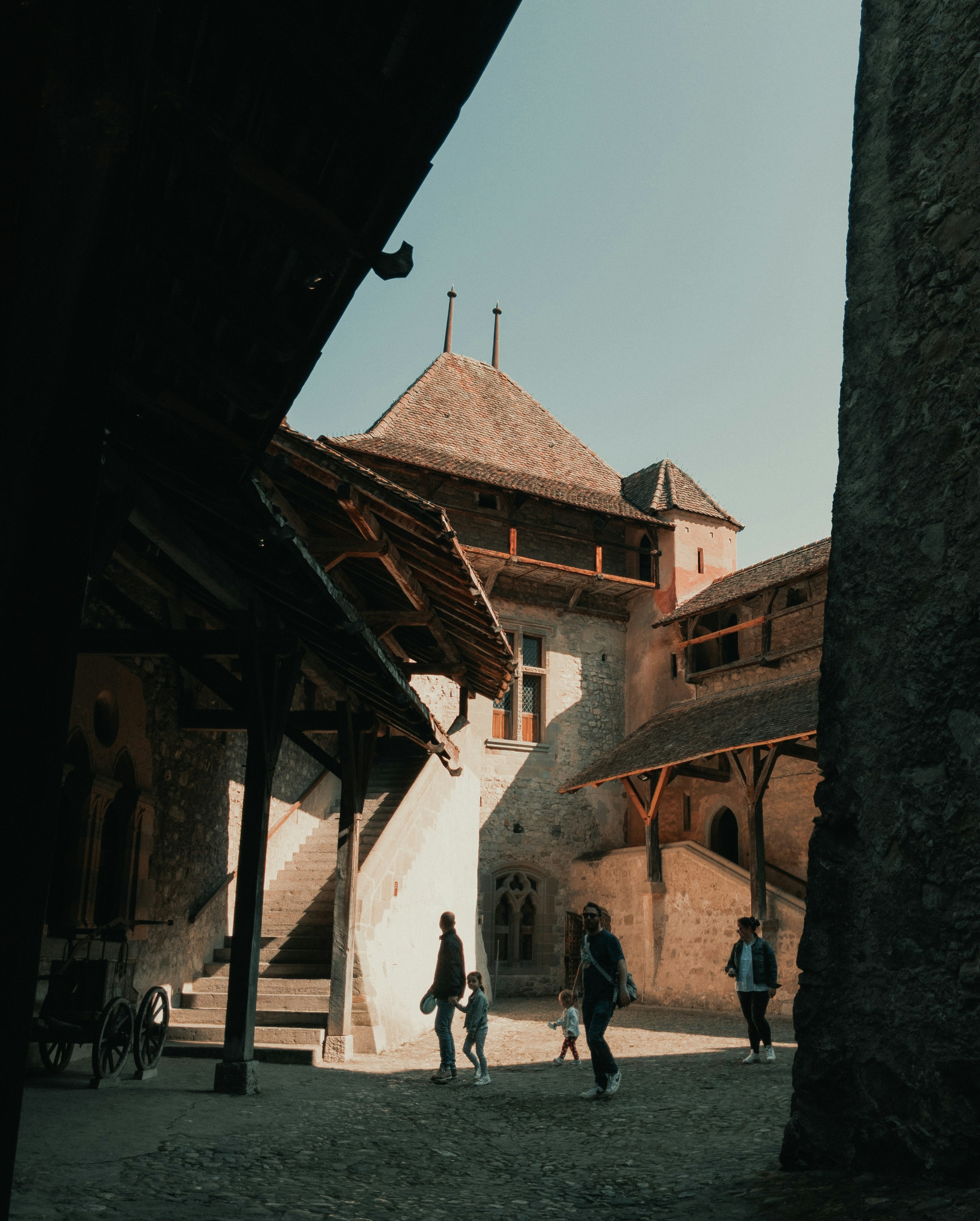 Sunlit Fortress Courtyard: Timbered Arches Frame a Towered Roof