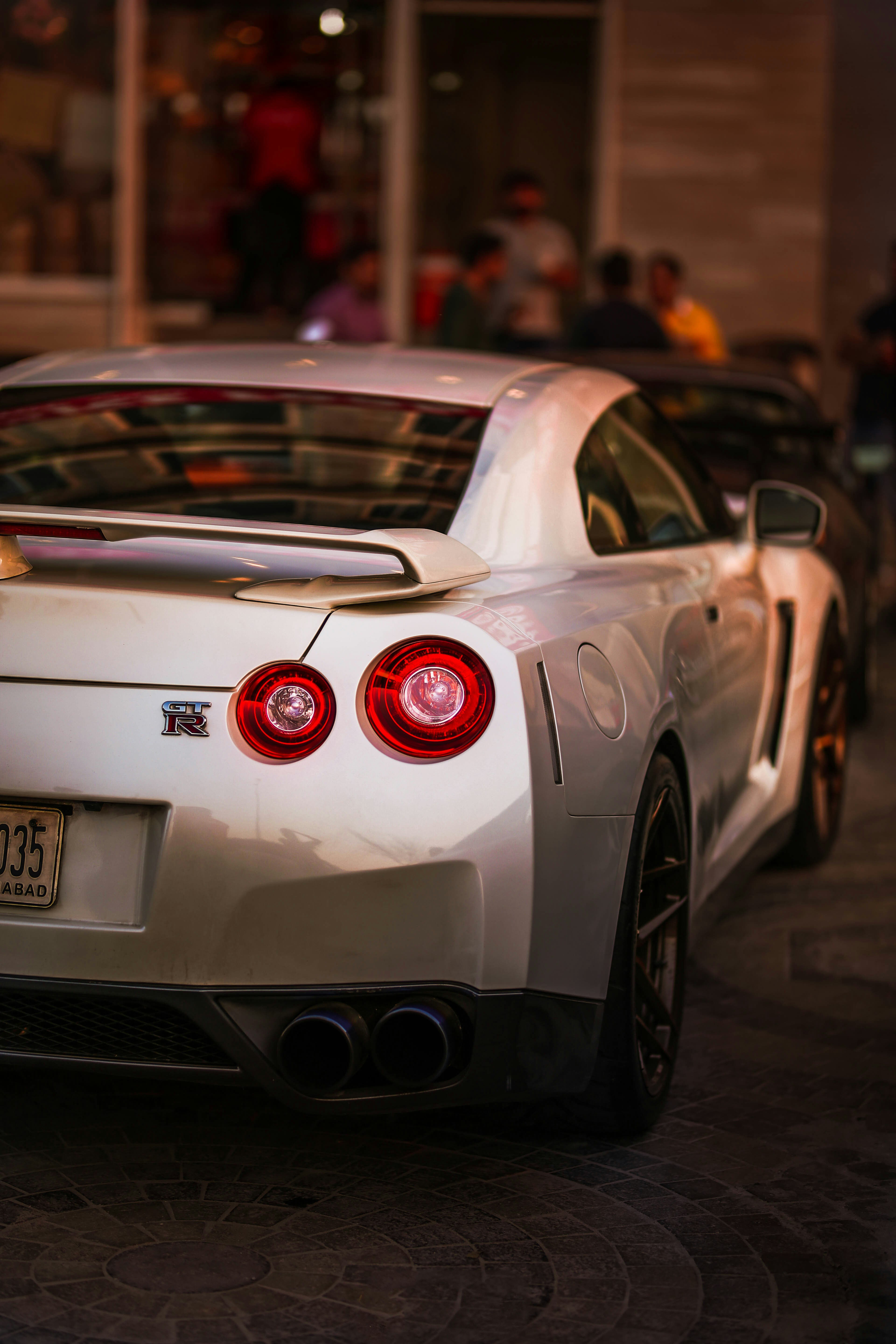 Rear view of a Nissan GT-R parked in an urban setting, showcasing its sleek design and distinctive taillights.
