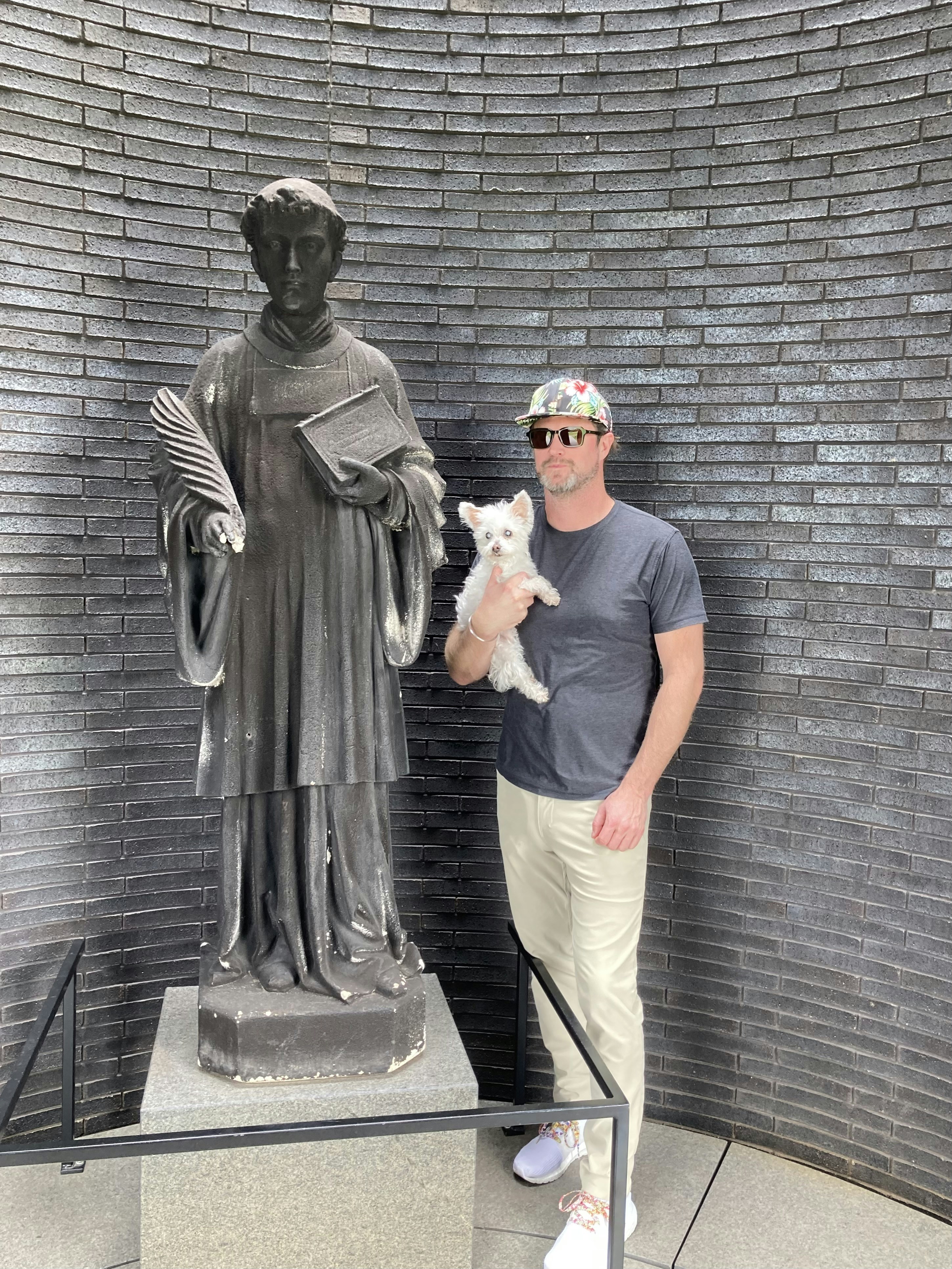 Hands-on Shrine: A man, tiny dog, and a statue within a curved brick alcove