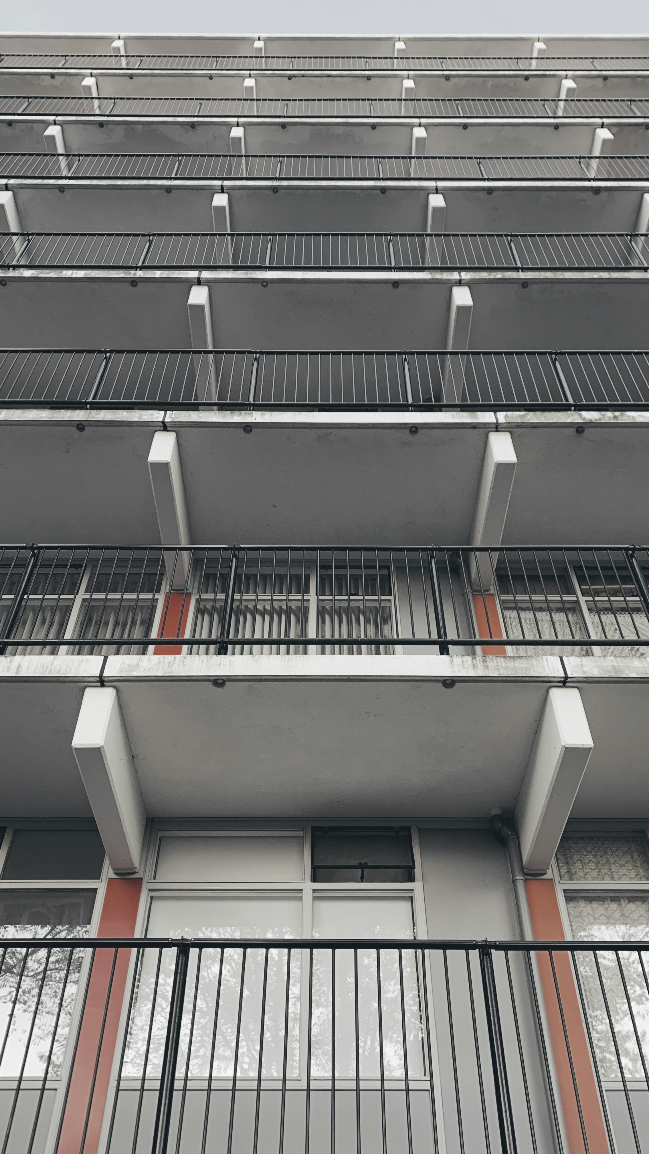 A close-up view of a multi-story building showcasing its balconies and structural lines in a monochromatic palette.