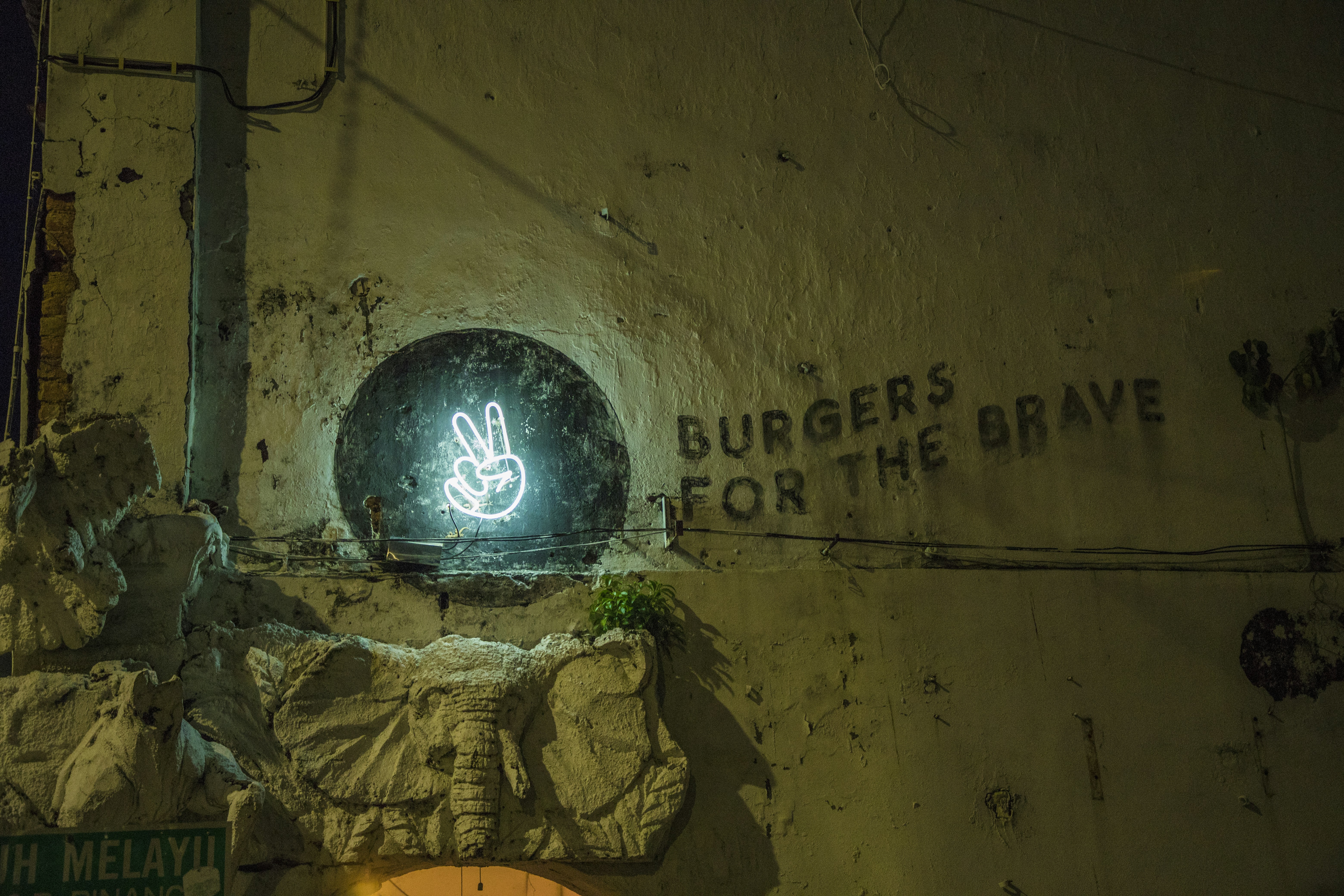 Neon Peace Sign Illuminates a Crumbling Basement Graffiti Wall