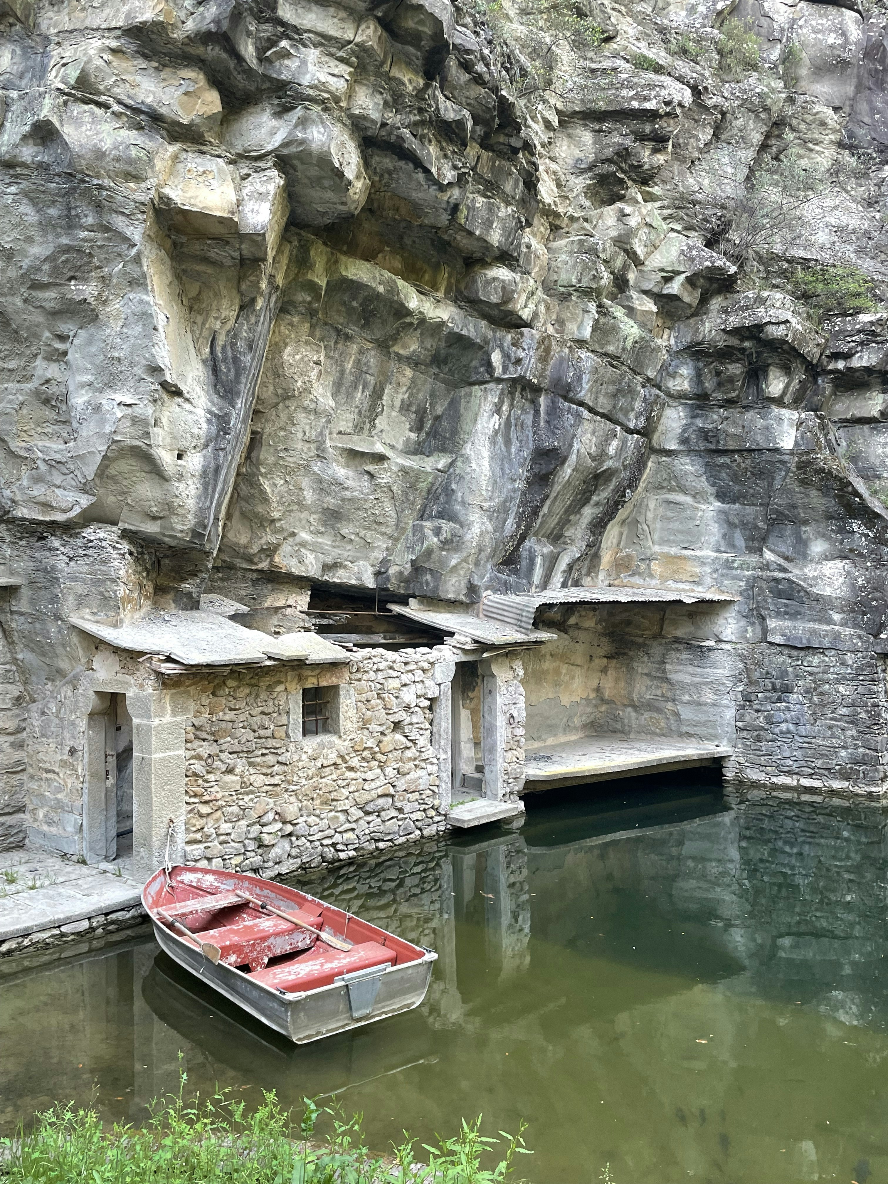 Red Dinghy at the Cliffside Stone Boathouse by a Quiet Pool