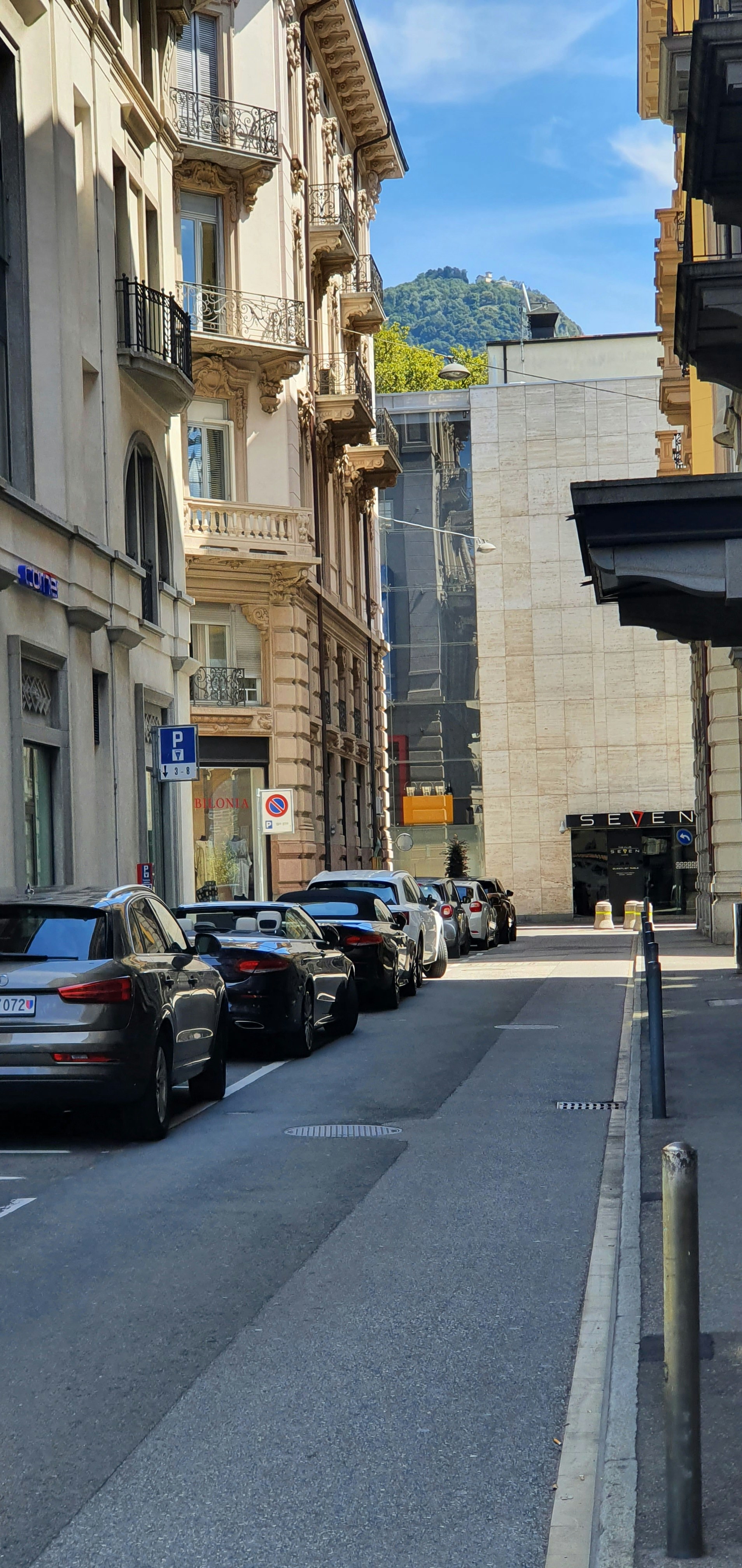 A city street lined with parked cars next to tall buildings photo ...