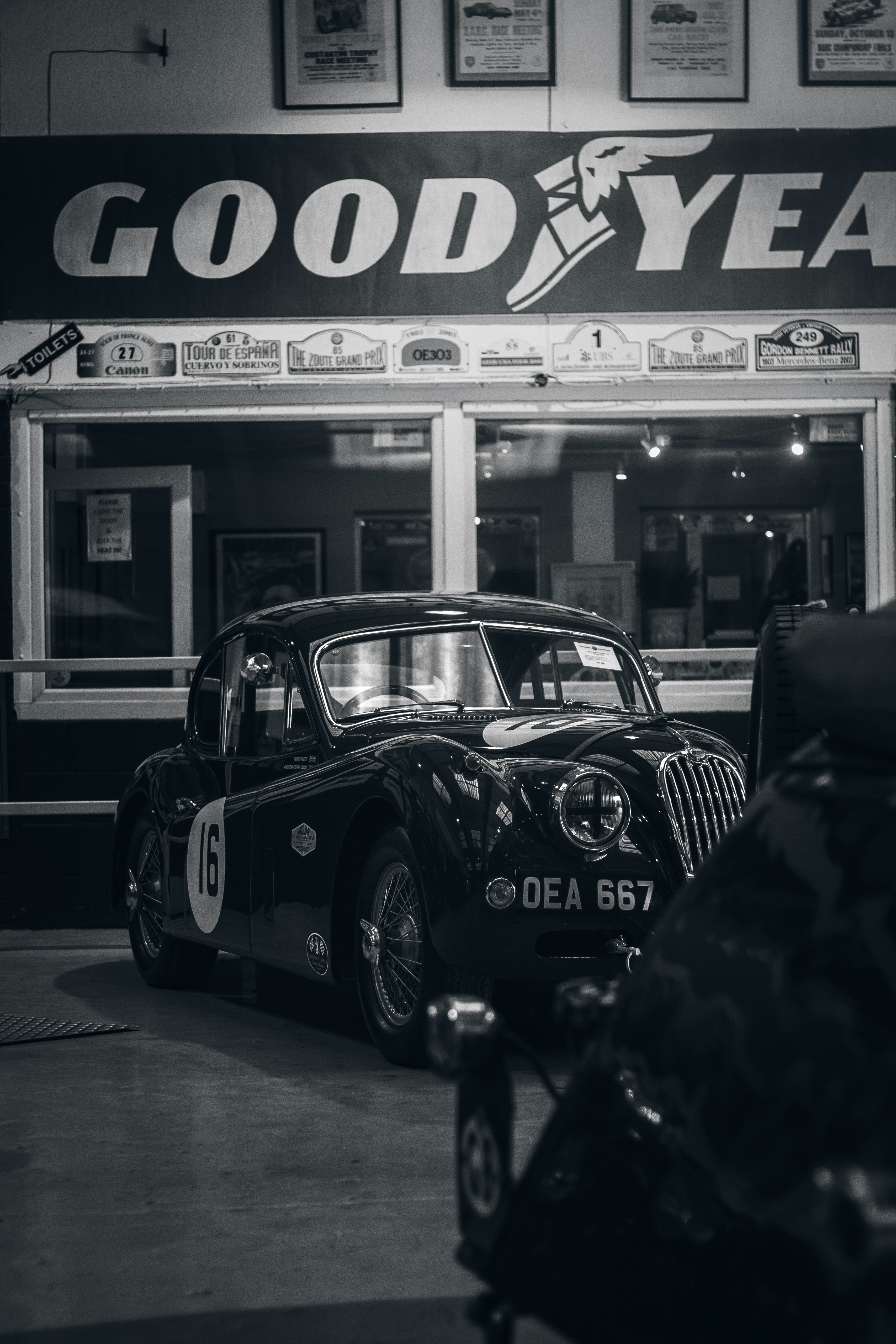 a black and white photo of a car parked in front of a store
