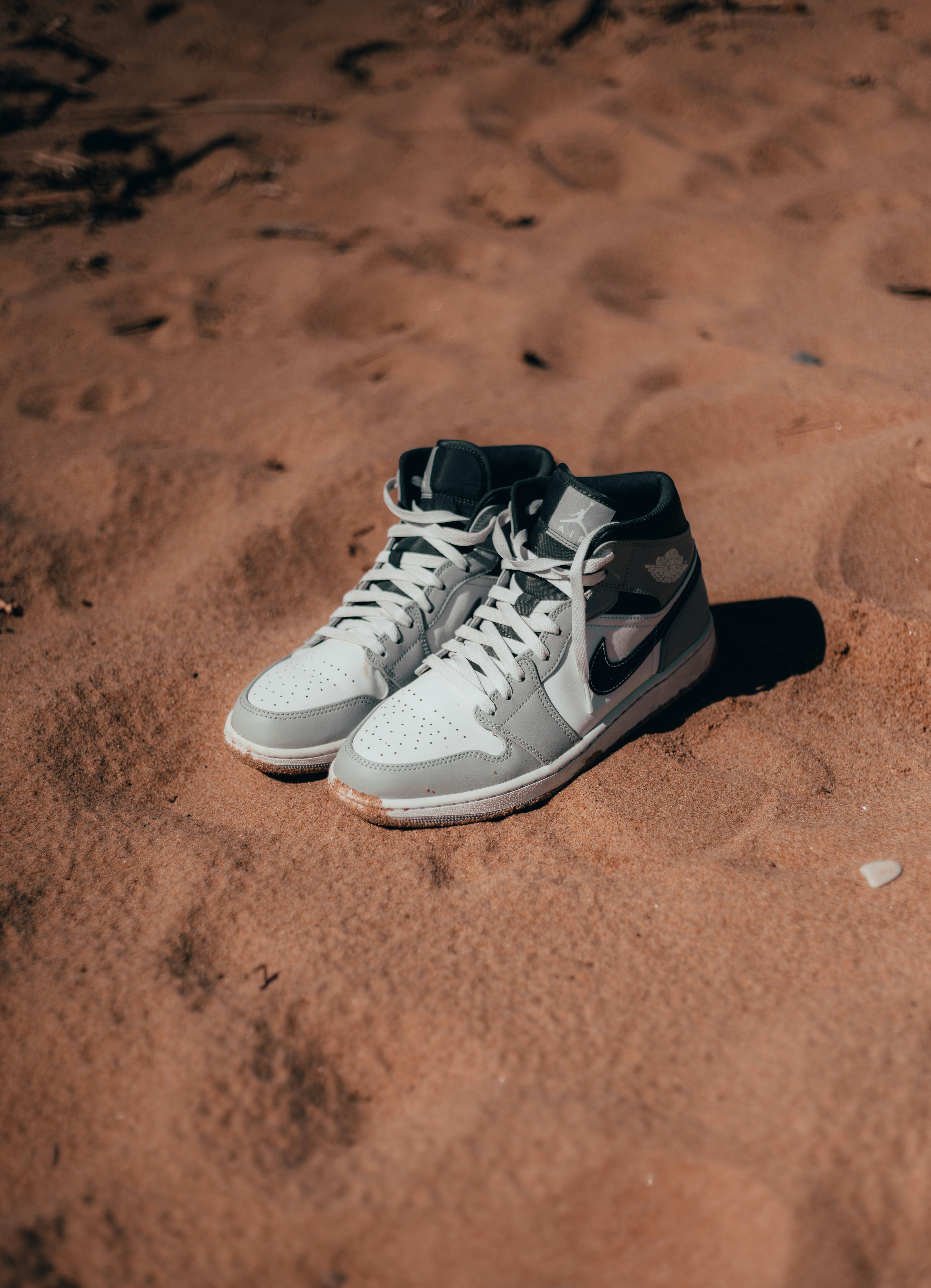 a pair of sneakers sitting on top of a sandy beach