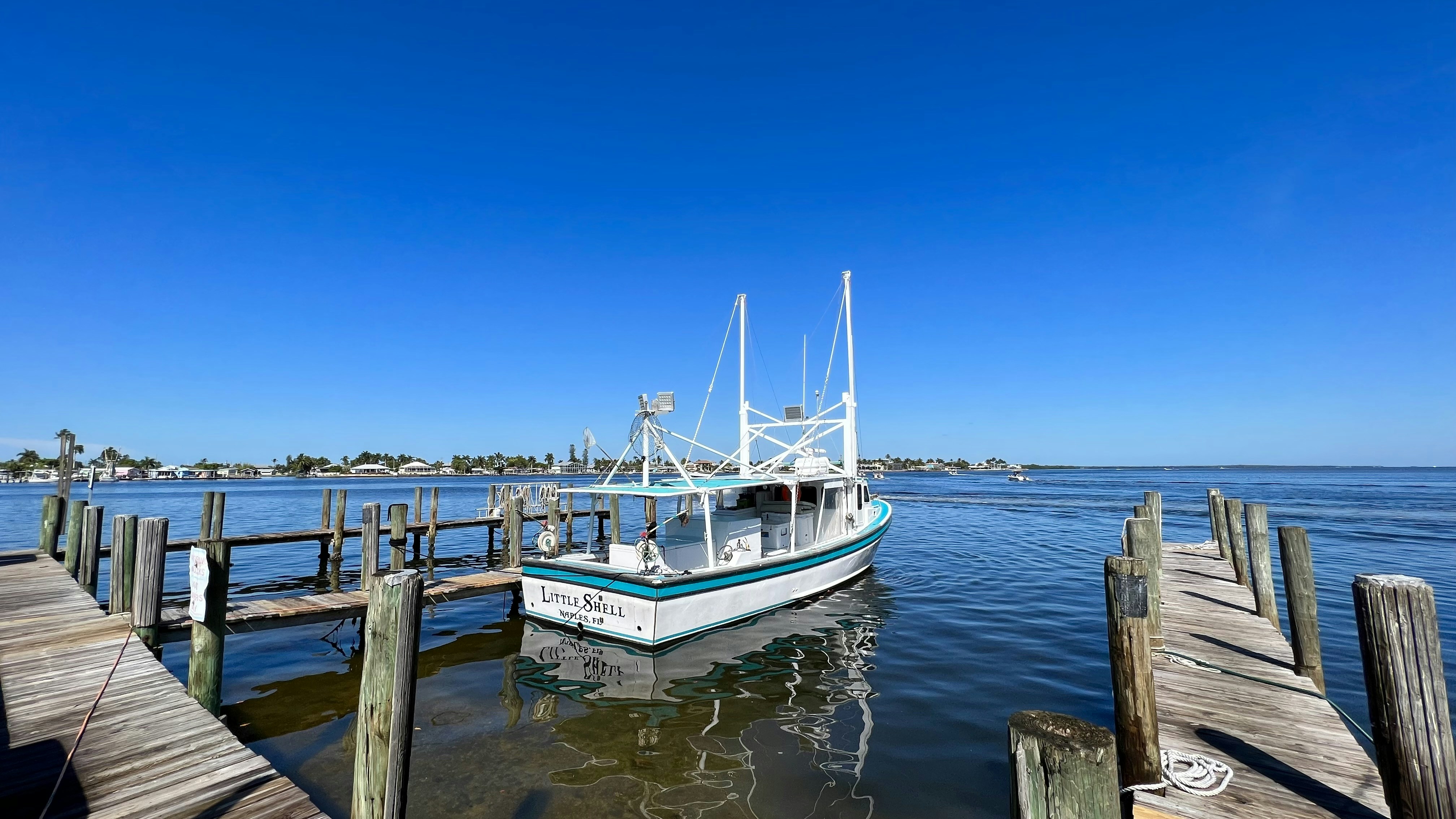 A boat is docked at a pier on a clear day photo – Free Matlacha Image ...