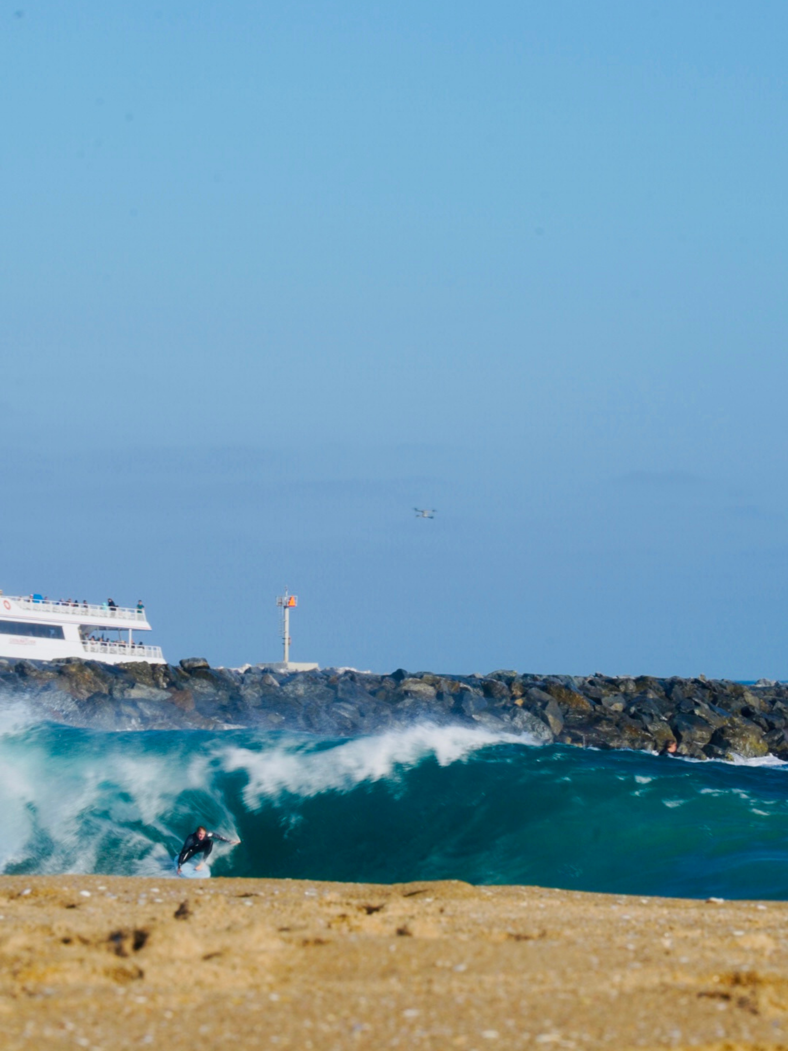 Foto Una persona surfeando una ola frente a un barco – Imagen Gris ...