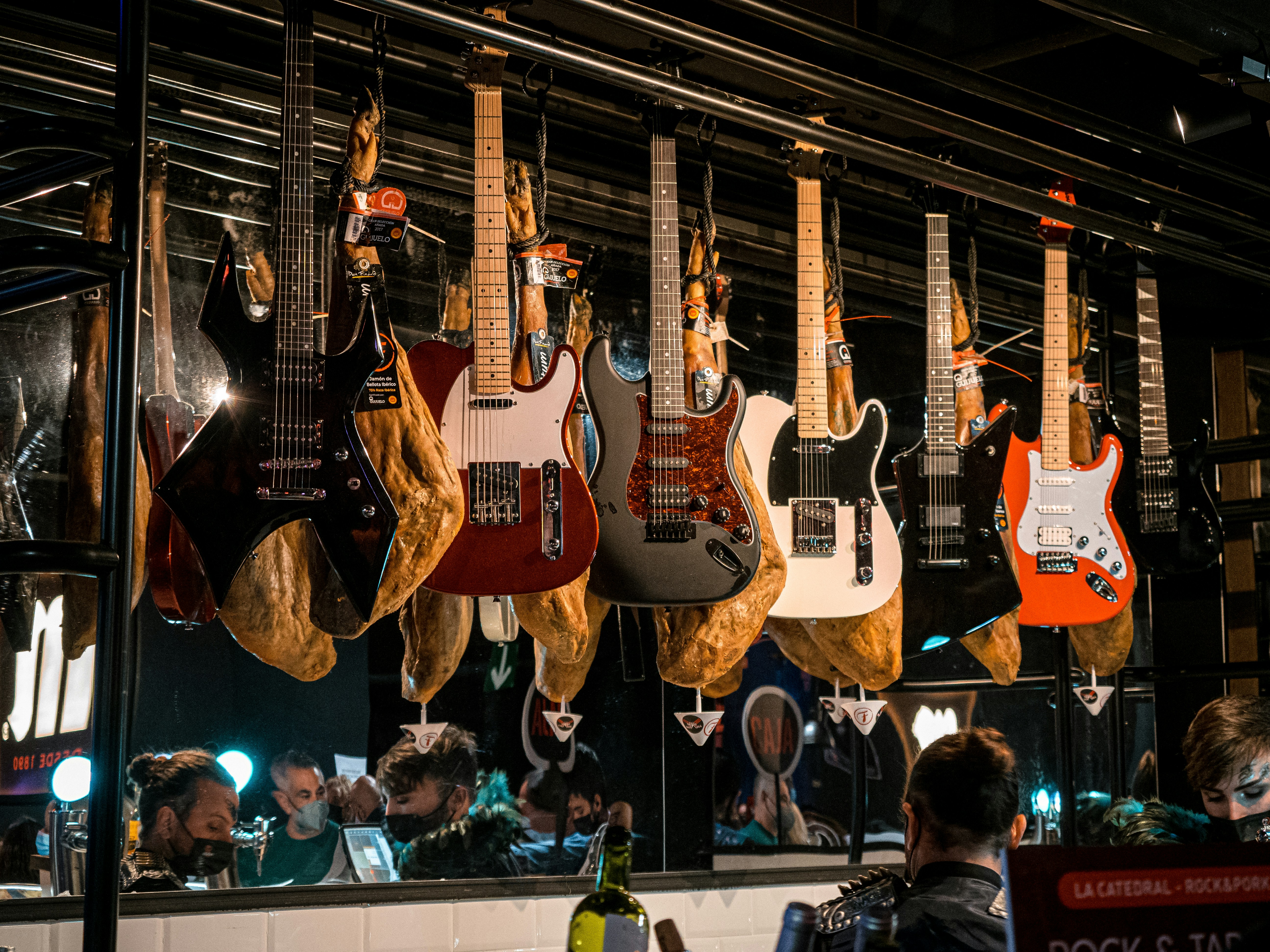 A group of guitars hanging from the ceiling photo – Free Human Image on ...