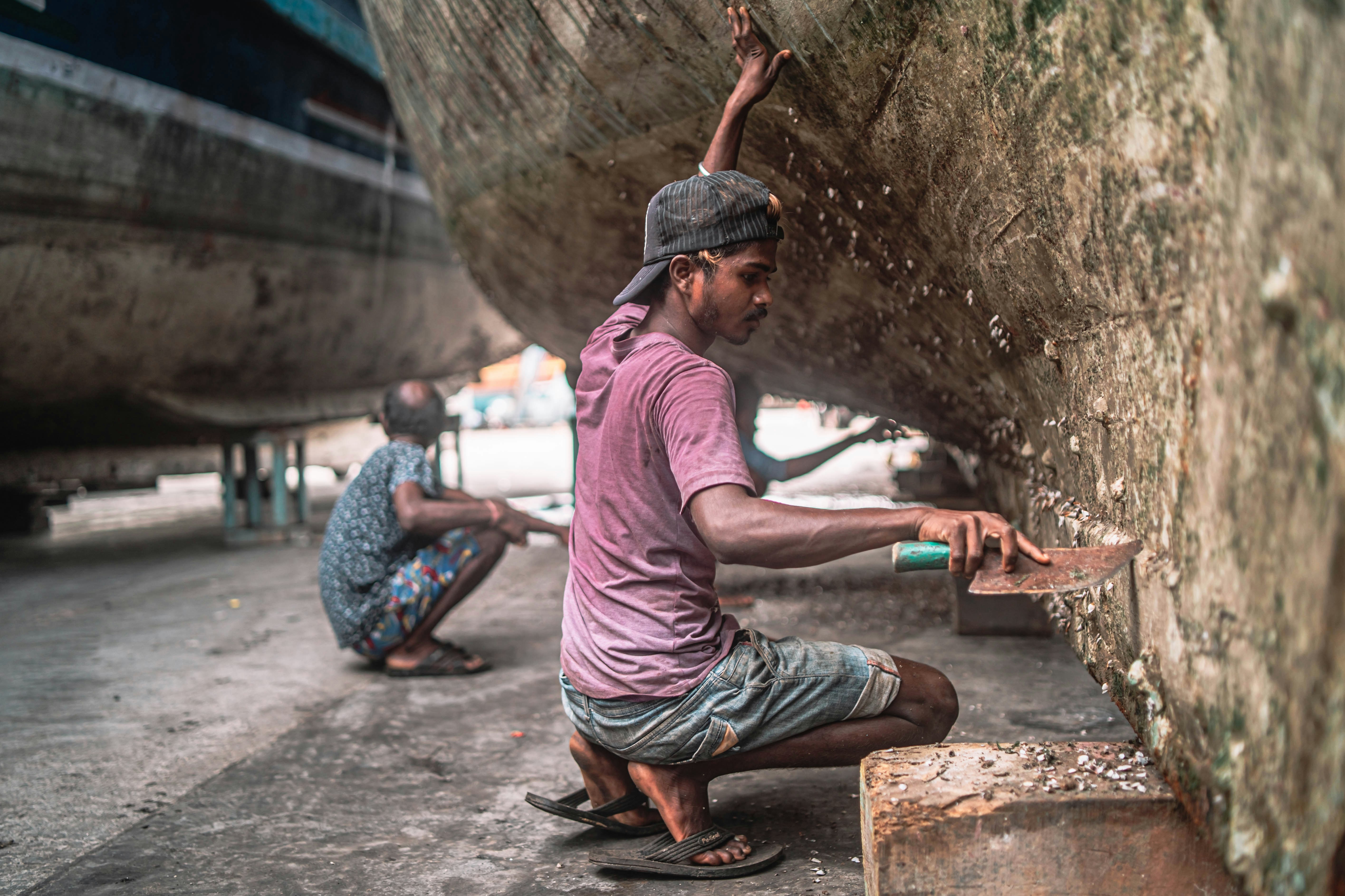Two men working on a boat in a shipyard photo – Free Person Image on ...