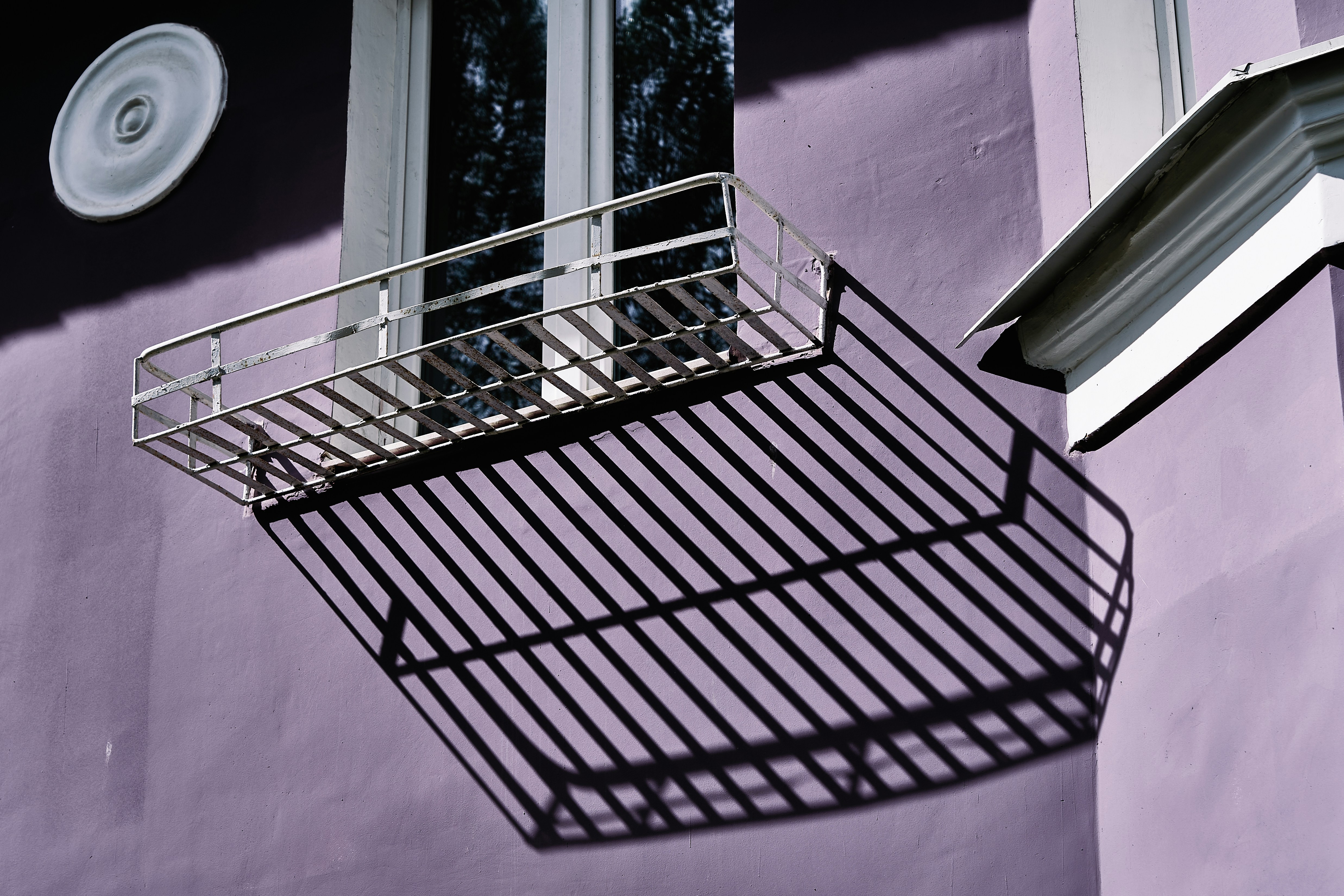 Shadowed Balcony Grille on a Violet Wall