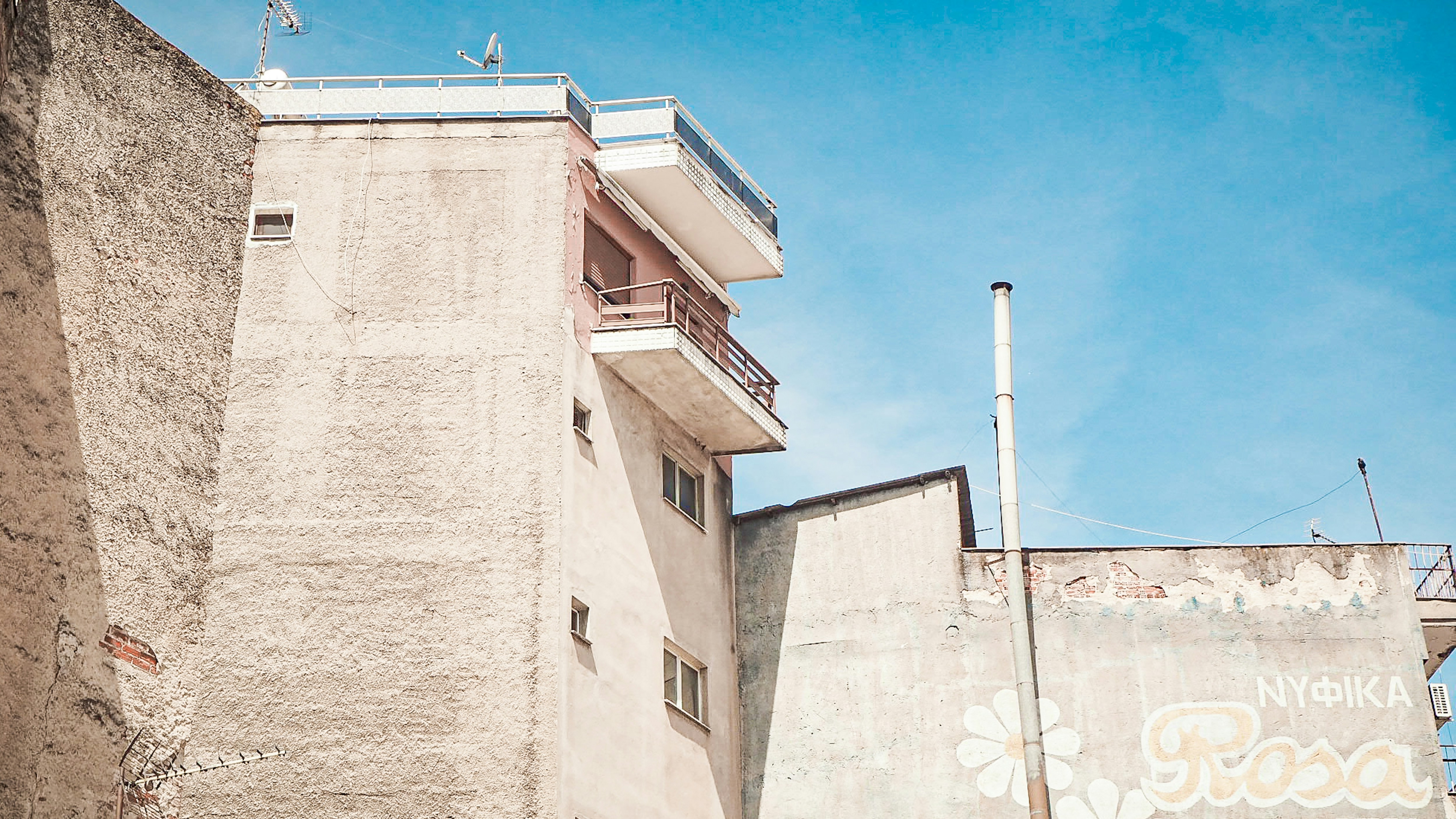 Weathered urban buildings against a clear blue sky.