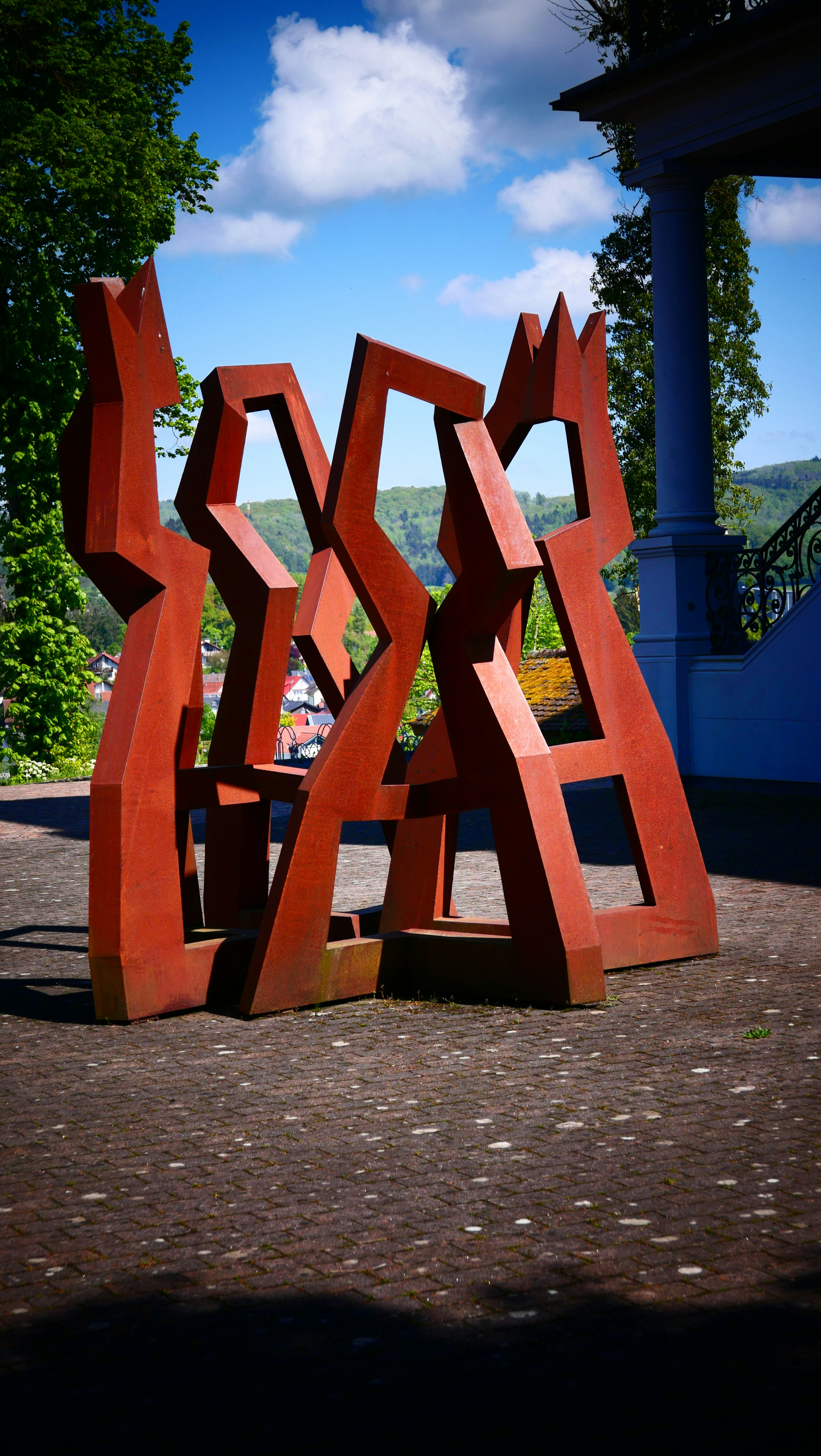 a large red sculpture sitting on top of a sidewalk photo – Free Park ...