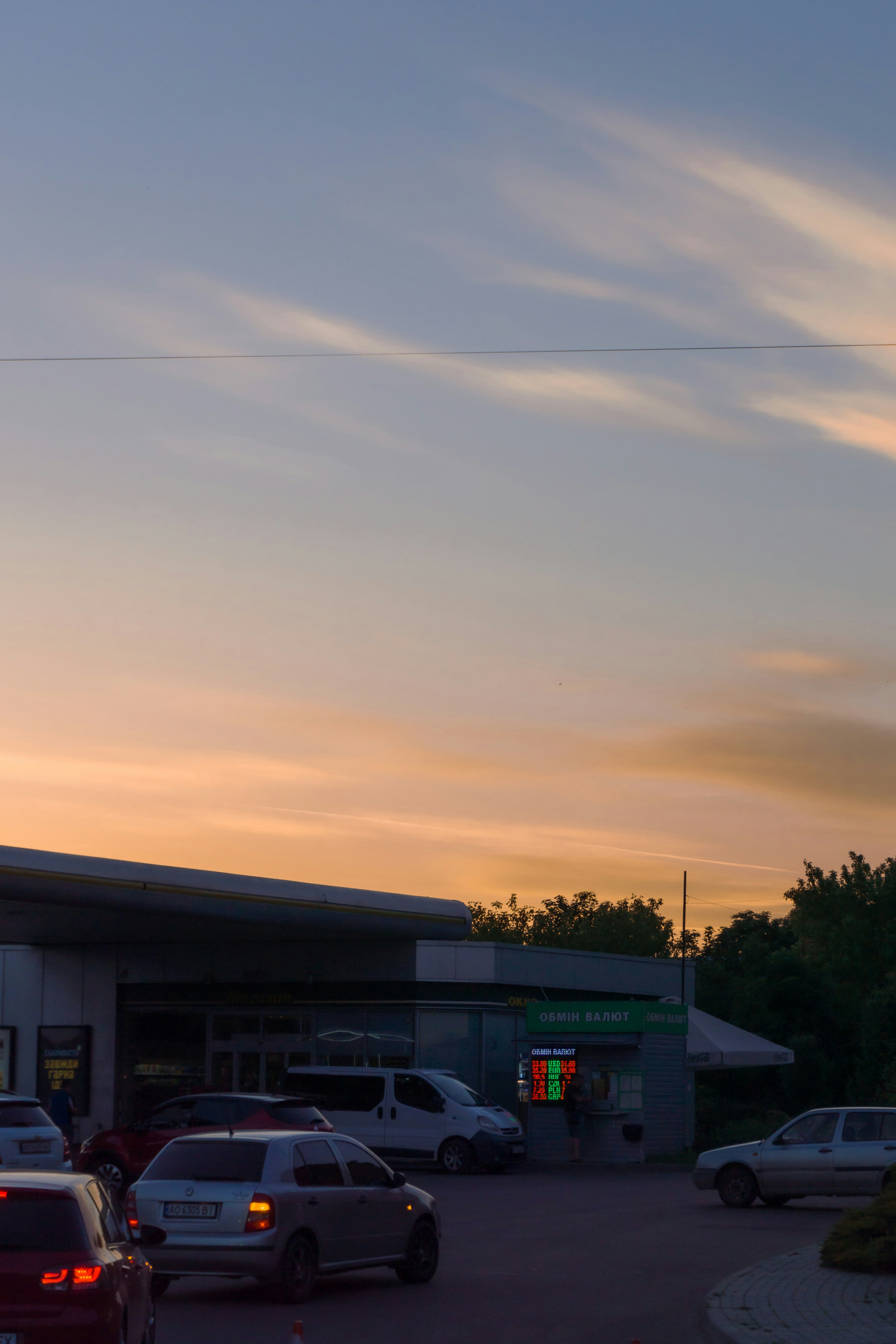Neon Pulse at Dusk Over a Suburban Market Parking Lot