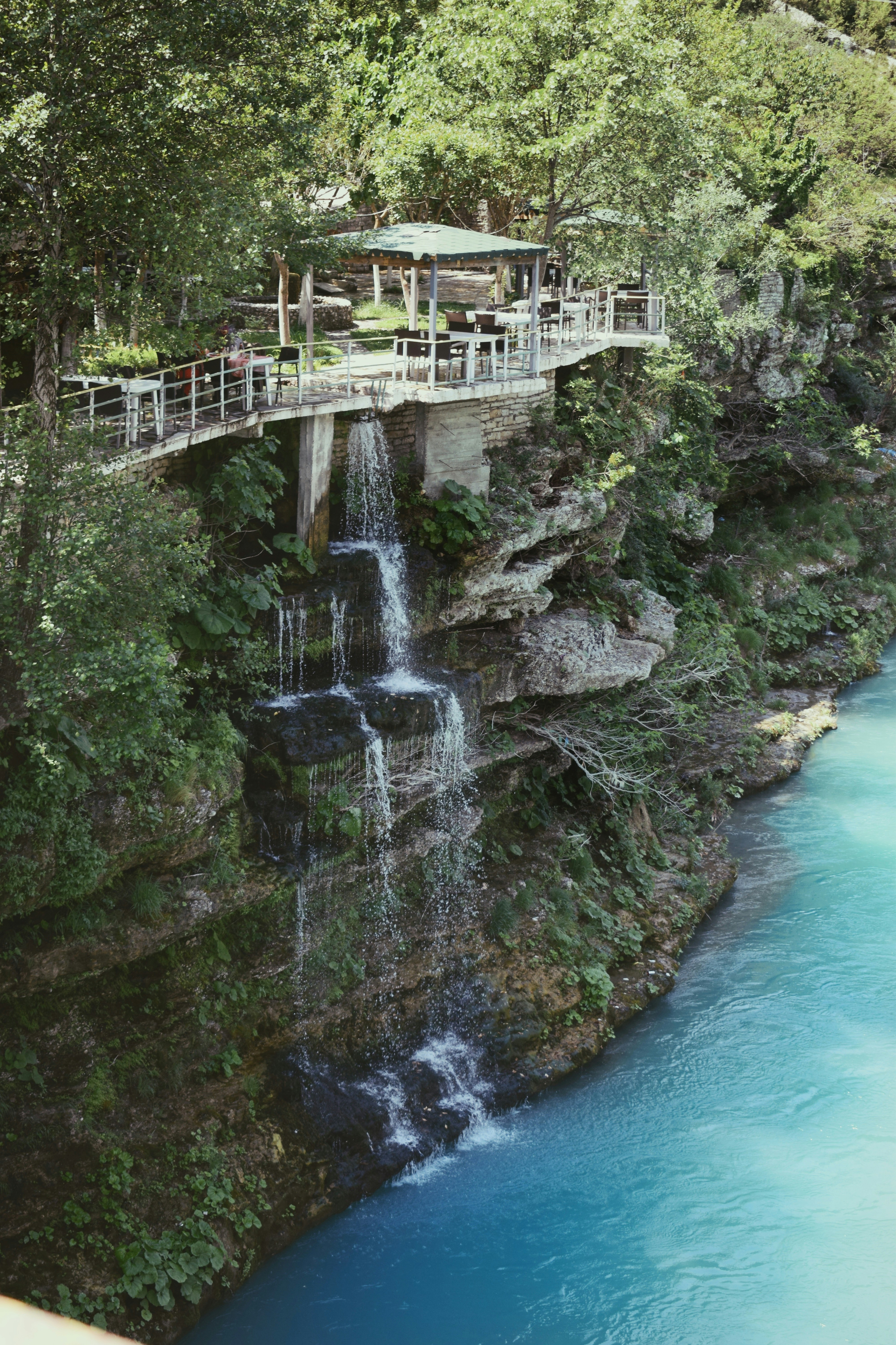 a waterfall with a bridge over it next to a river