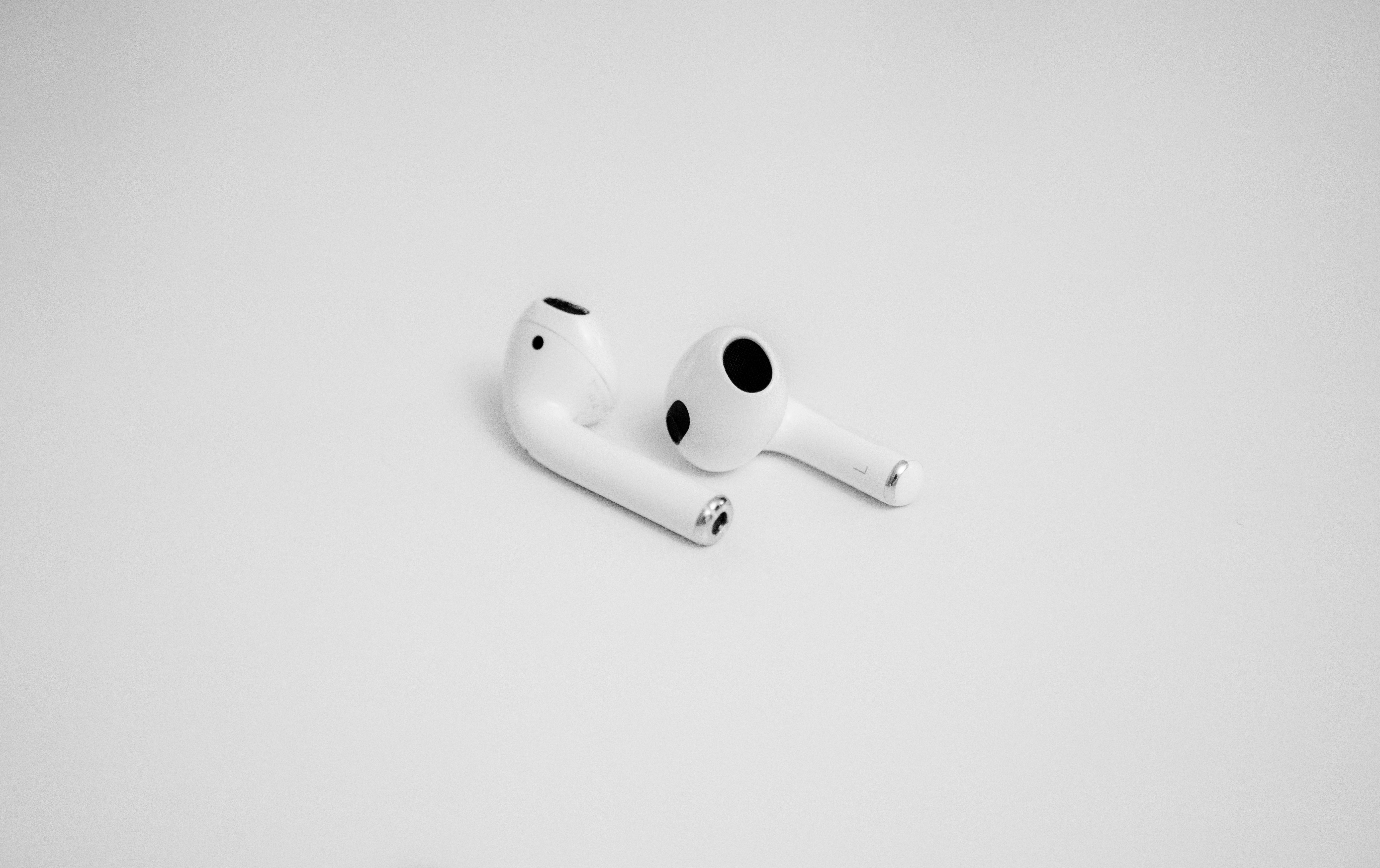 Two white wireless earbuds resting on a smooth surface, showcasing their sleek design and modern aesthetic.