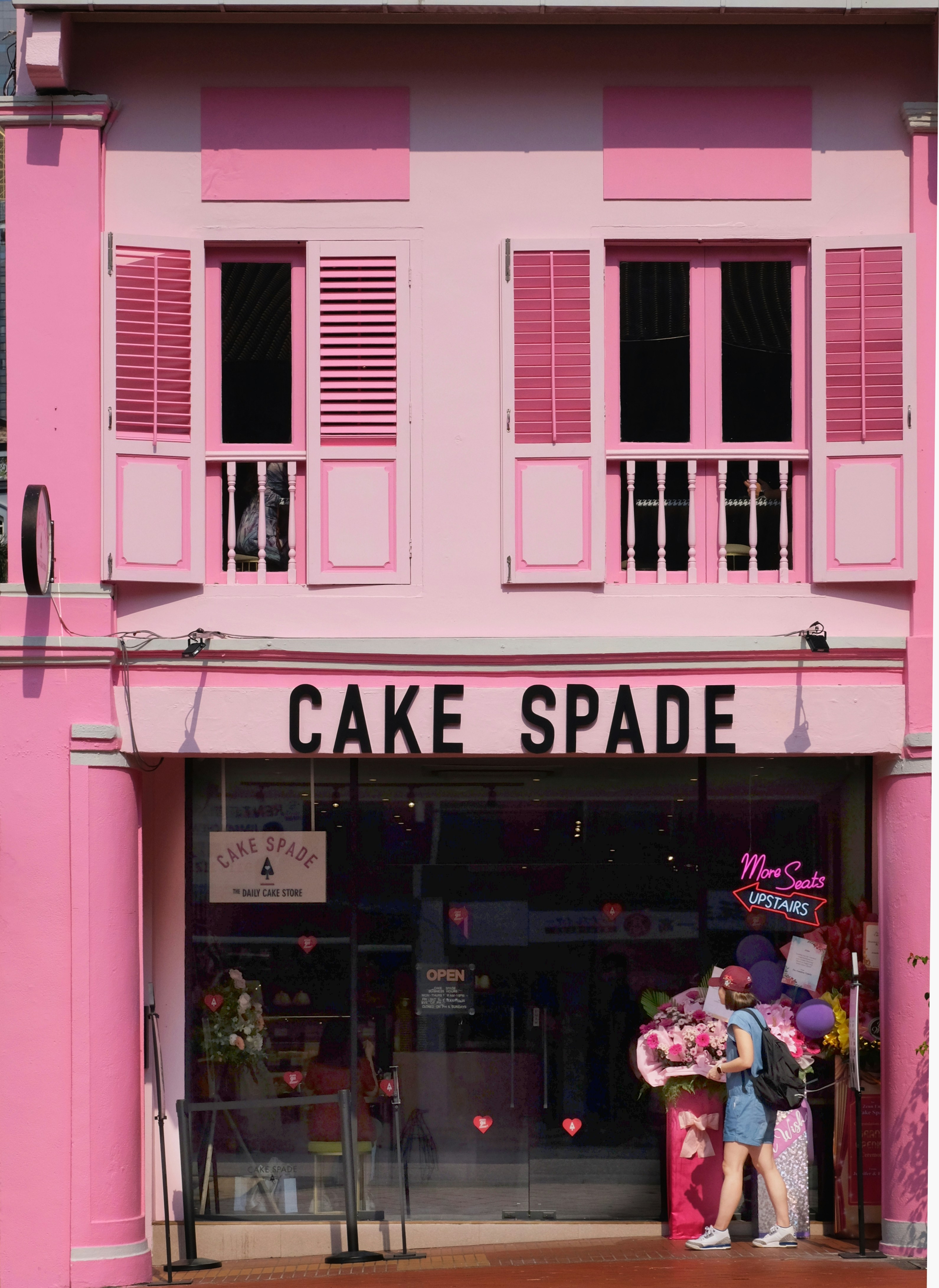 A pink building with pink shutters and a woman holding a pink umbrella ...