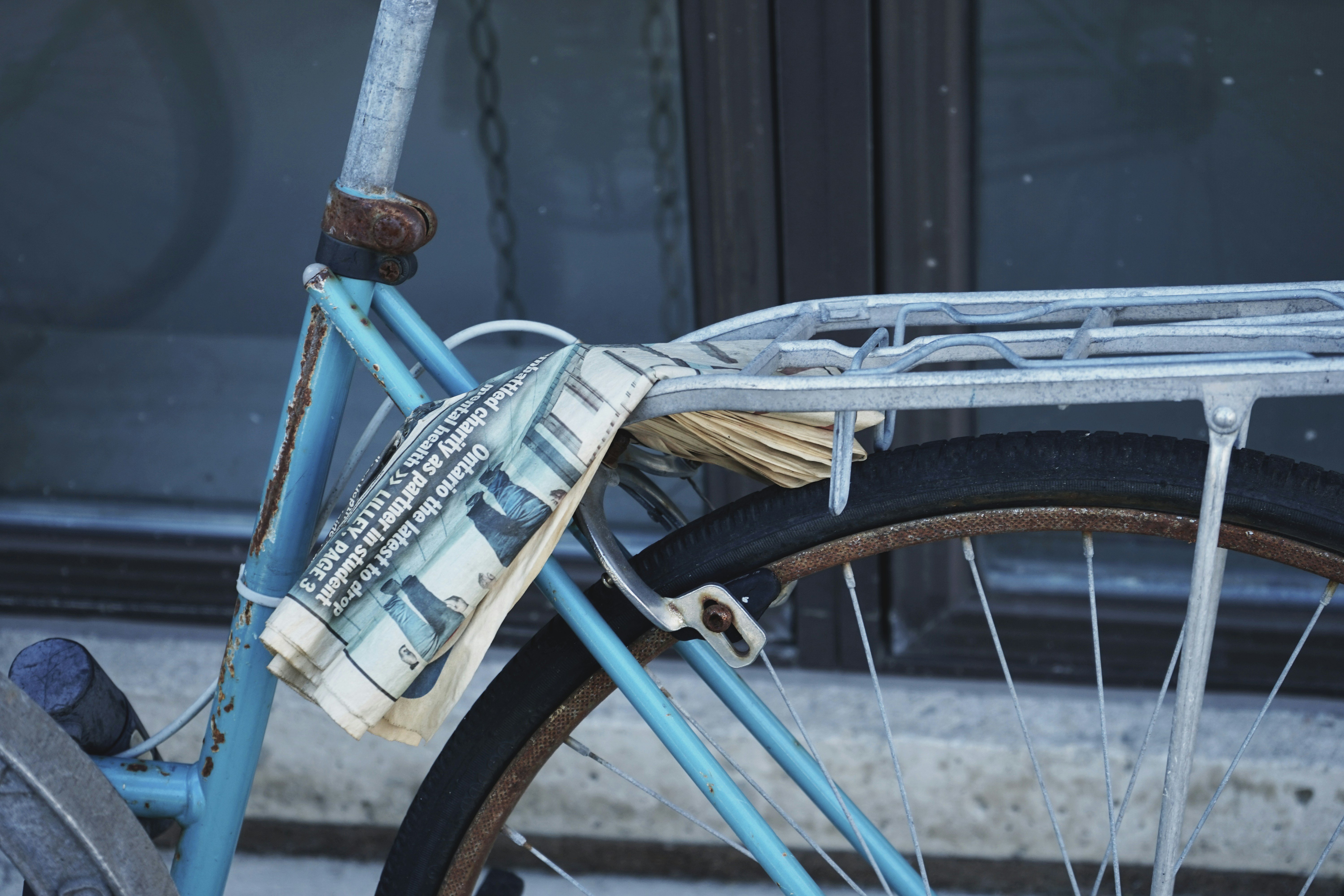 Vintage bicycle adorned with a weathered newspaper resting on its rear rack, showcasing urban charm and nostalgia.