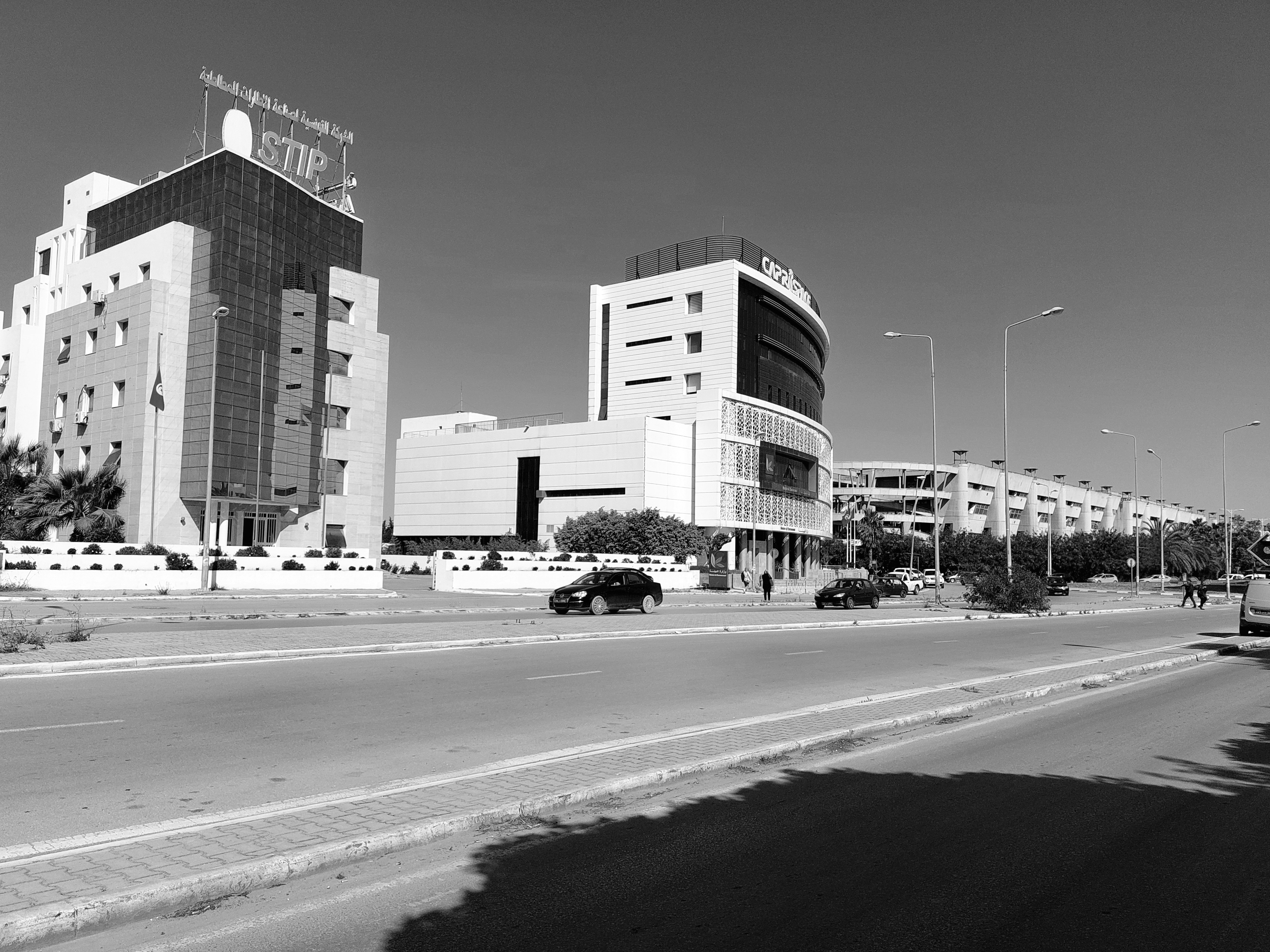 Modern buildings lining a busy road, showcasing contemporary architectural designs and urban life.