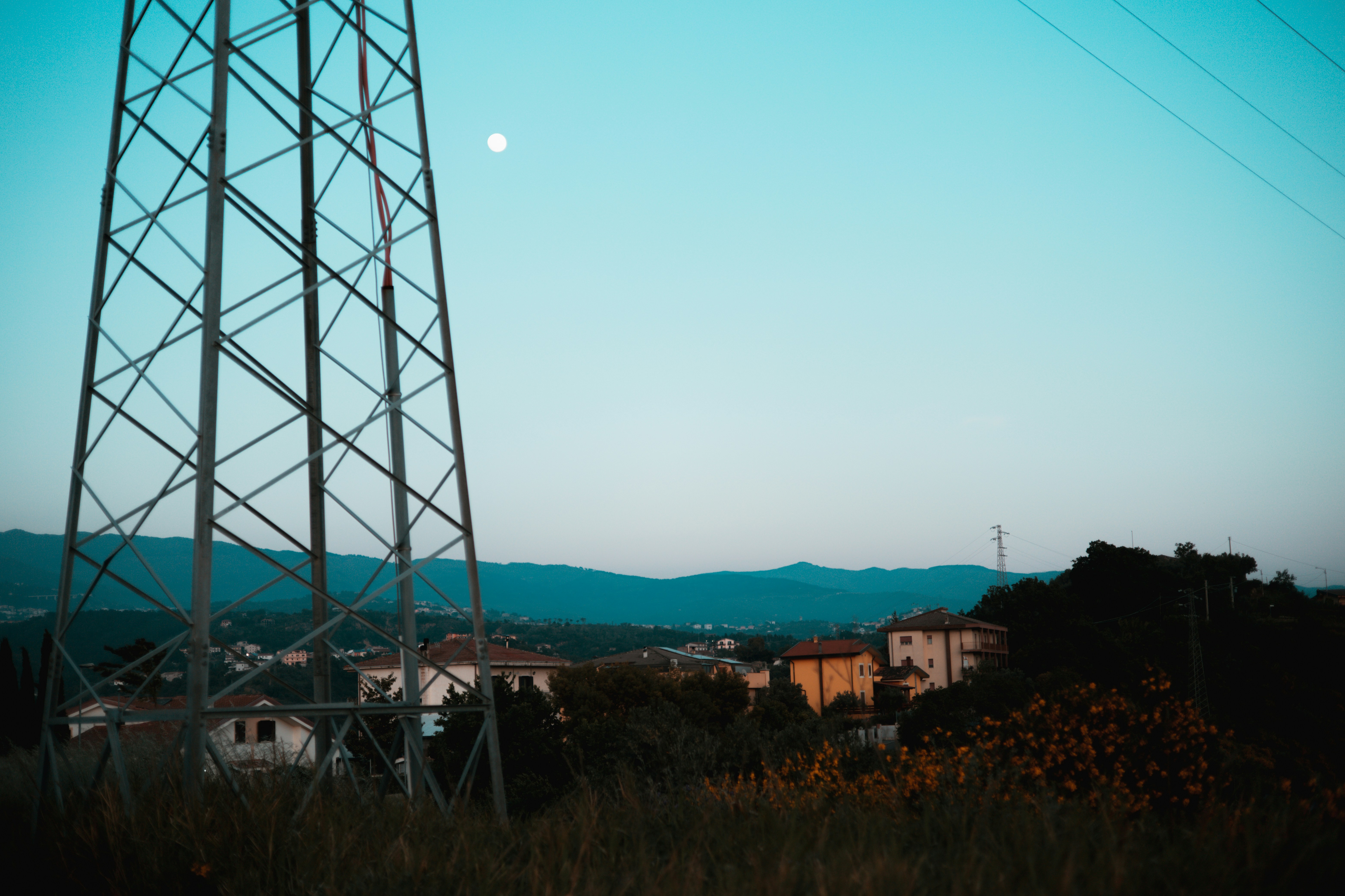A full moon is seen in the distance behind power lines photo – Free ...