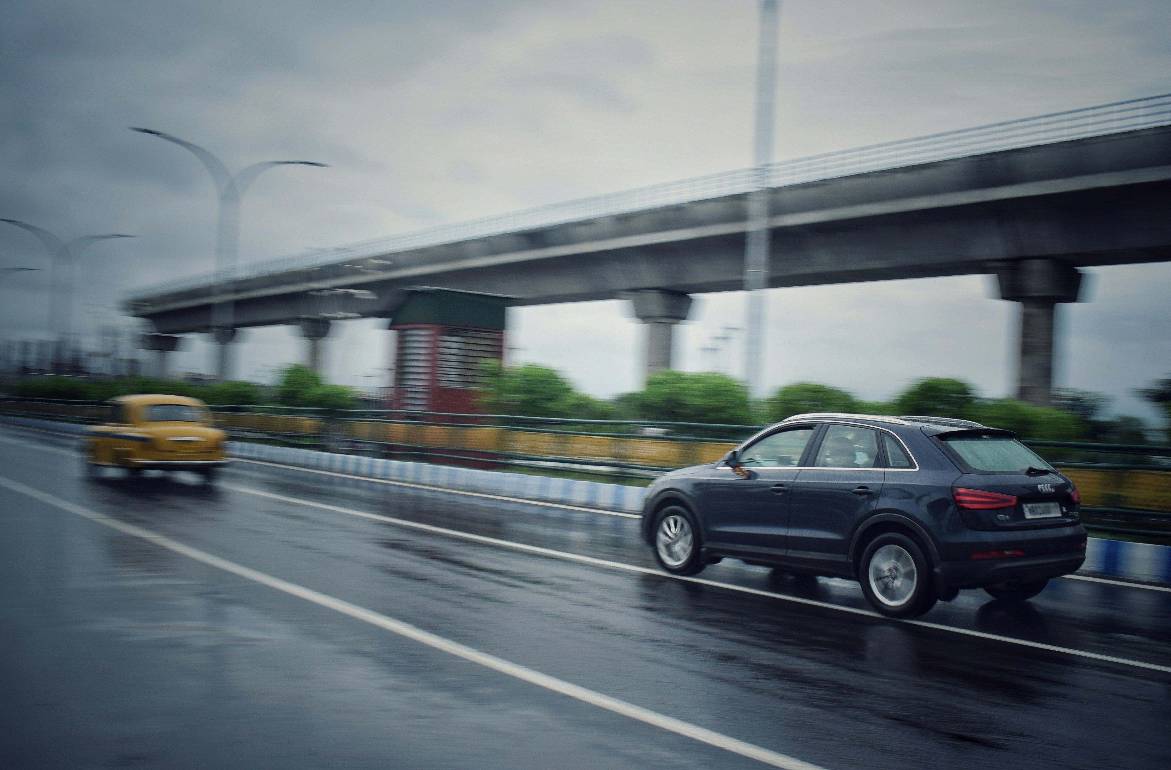 Foto Un coche conduciendo por una carretera mojada junto a un puente ...