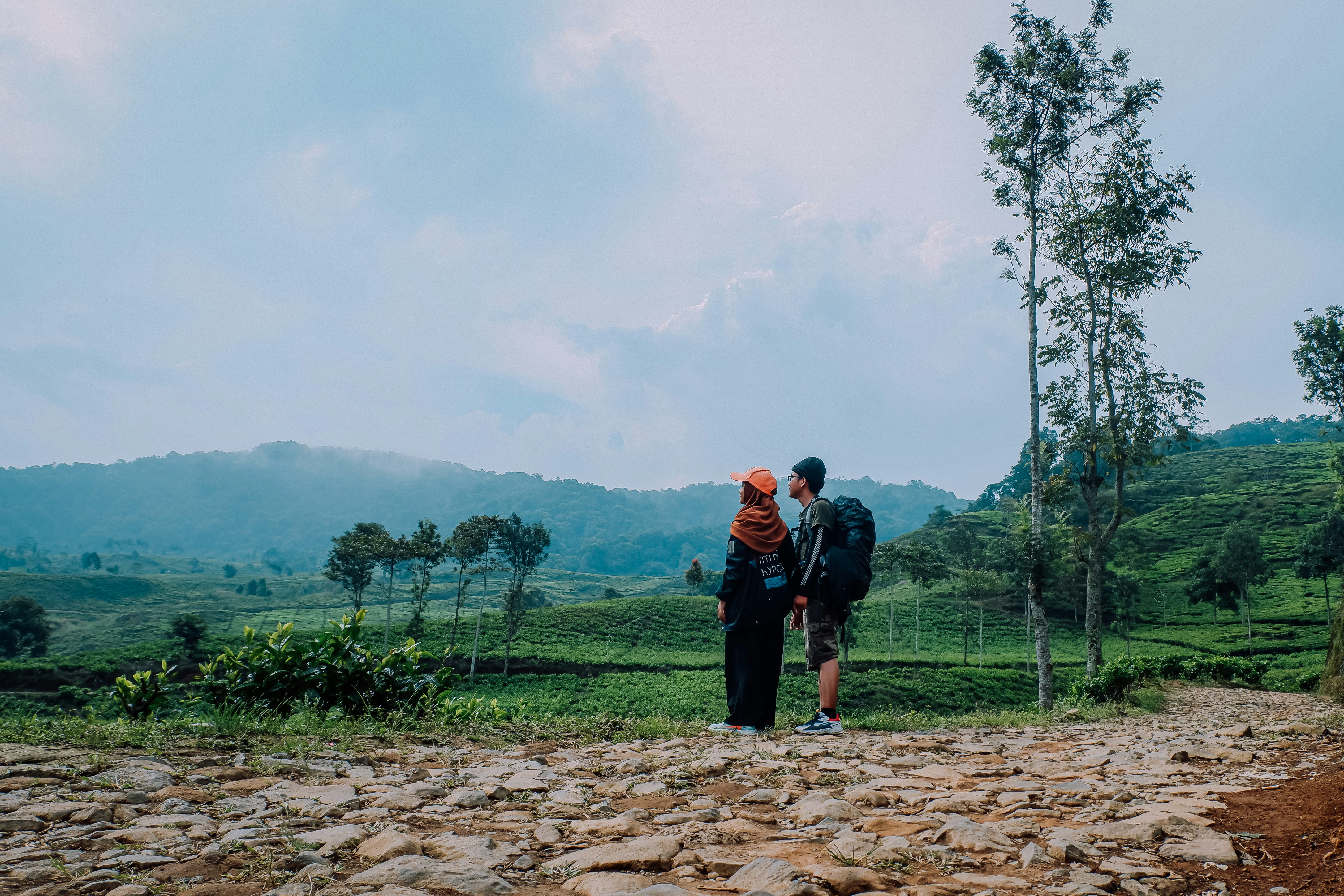 a couple of people standing on top of a dirt road