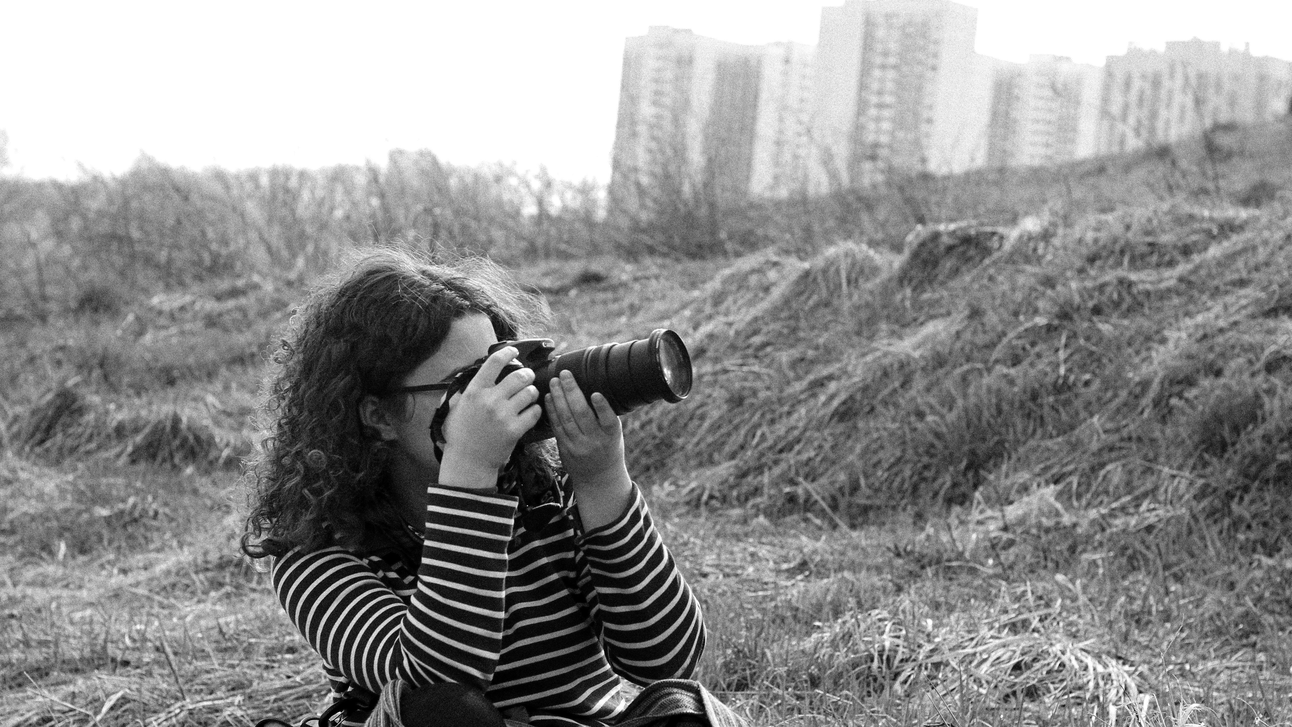 a woman sitting on the ground taking a picture with a camera