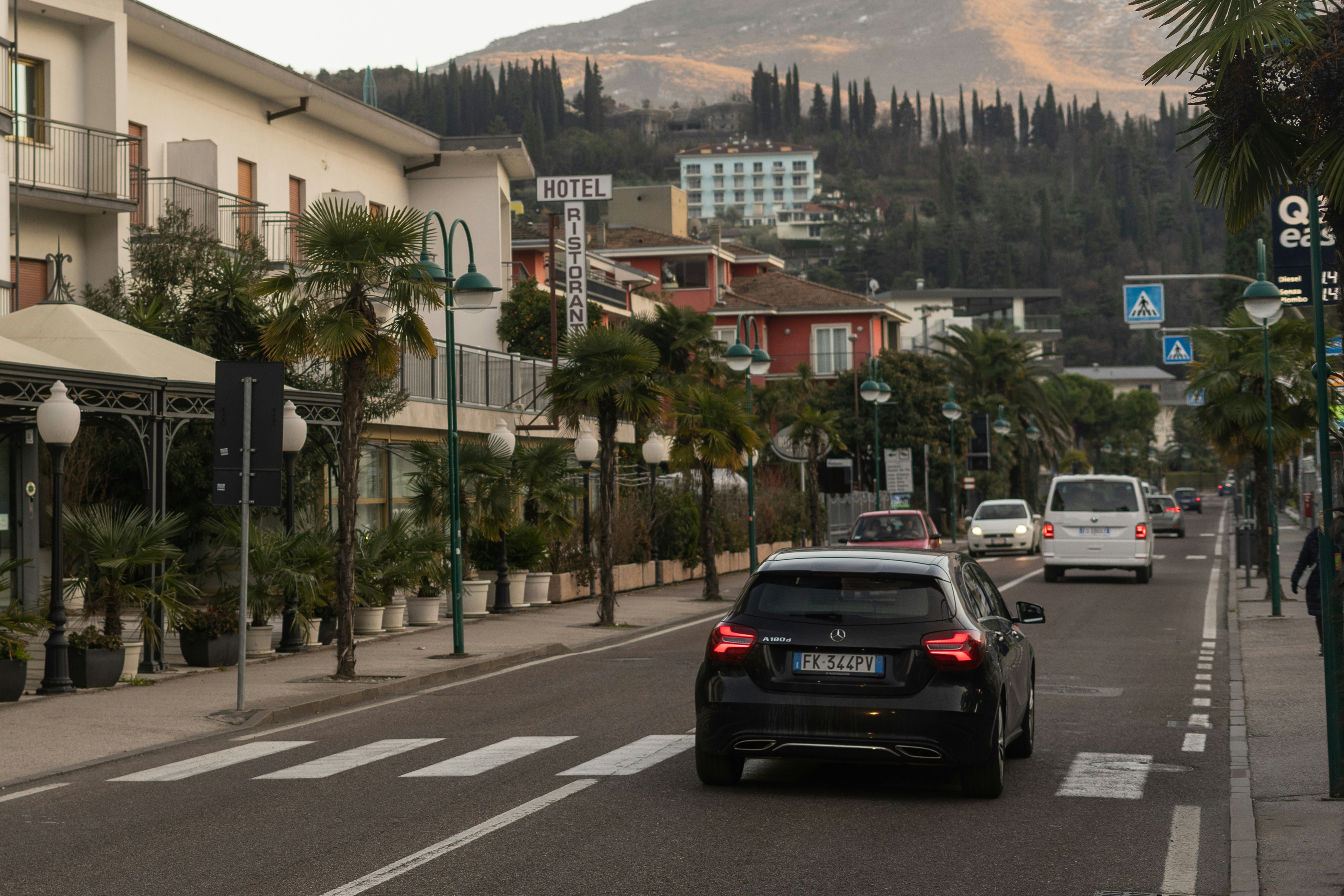 Black SUV on a Palm-Lined Coastal Street as Hills Fade Behind