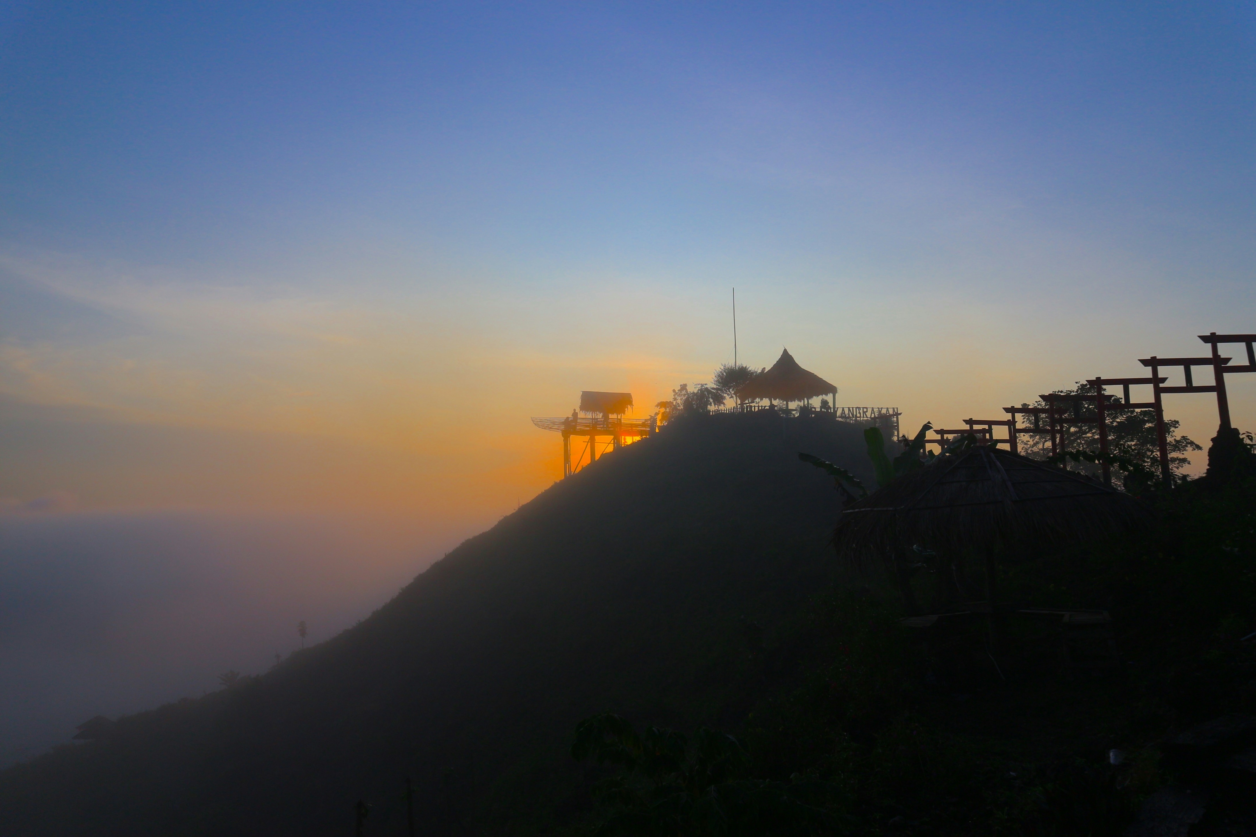 The sun is setting over a hill with a tower on top photo – Free ...