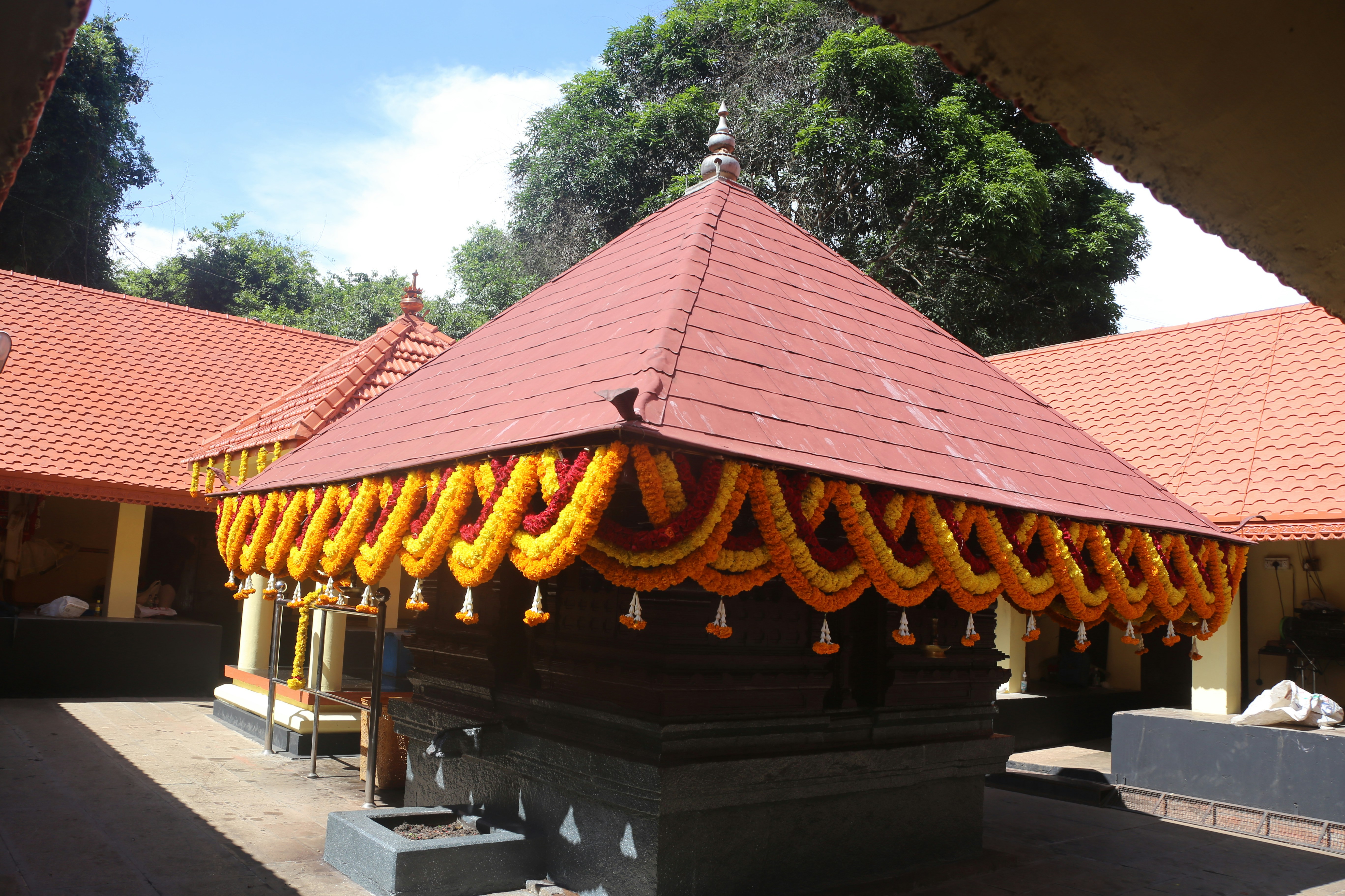 A temple with a red roof and yellow garlands photo – Free Pallipuram ...