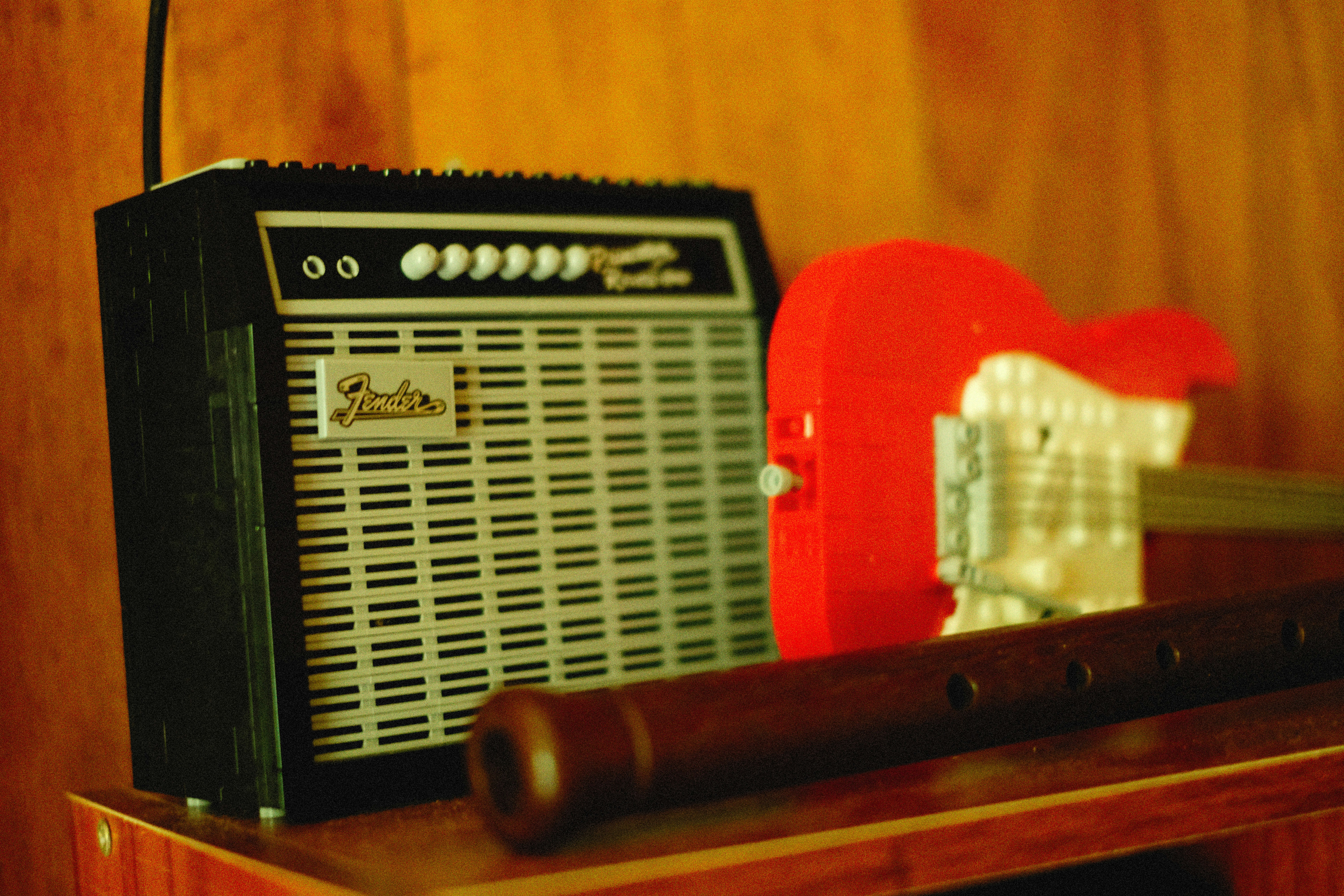 A vintage amplifier sits alongside a colorful toy guitar and a wooden flute, capturing a nostalgic blend of music and creativity.