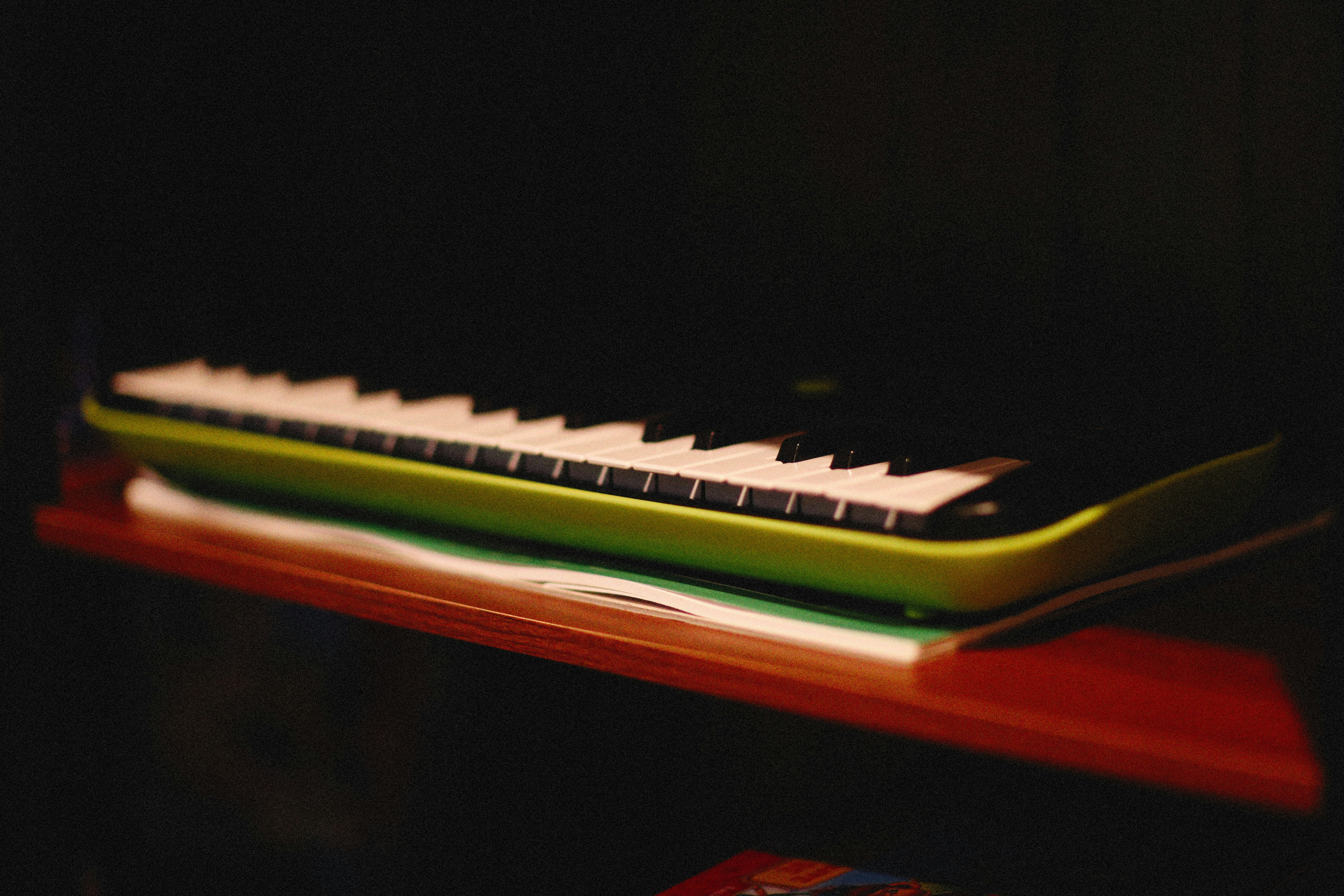 a green and white keyboard sitting on top of a wooden table