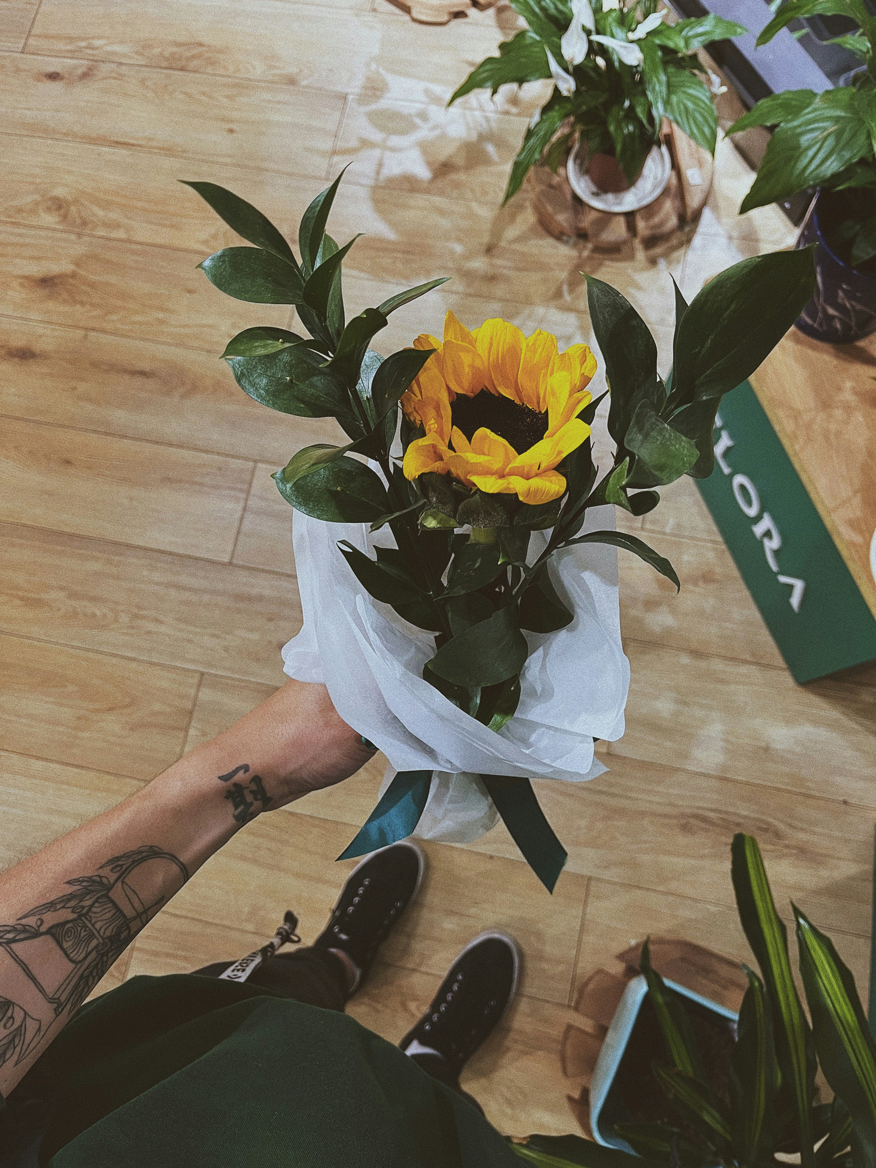 Bouquet Triumph: A Handheld Moment Framed by Feet and Sunflower