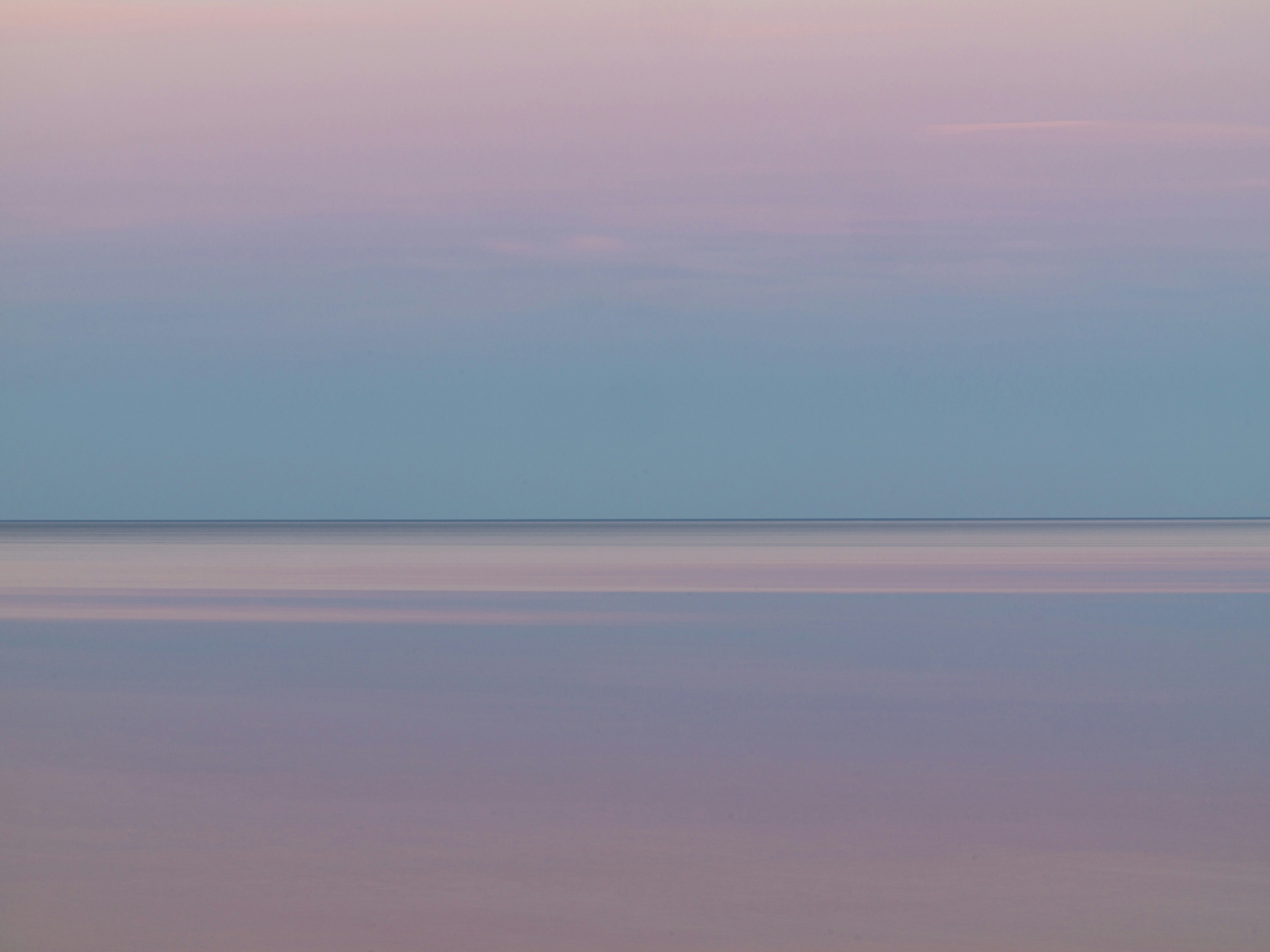 Calm waters under a gradient sky of purple and blue.