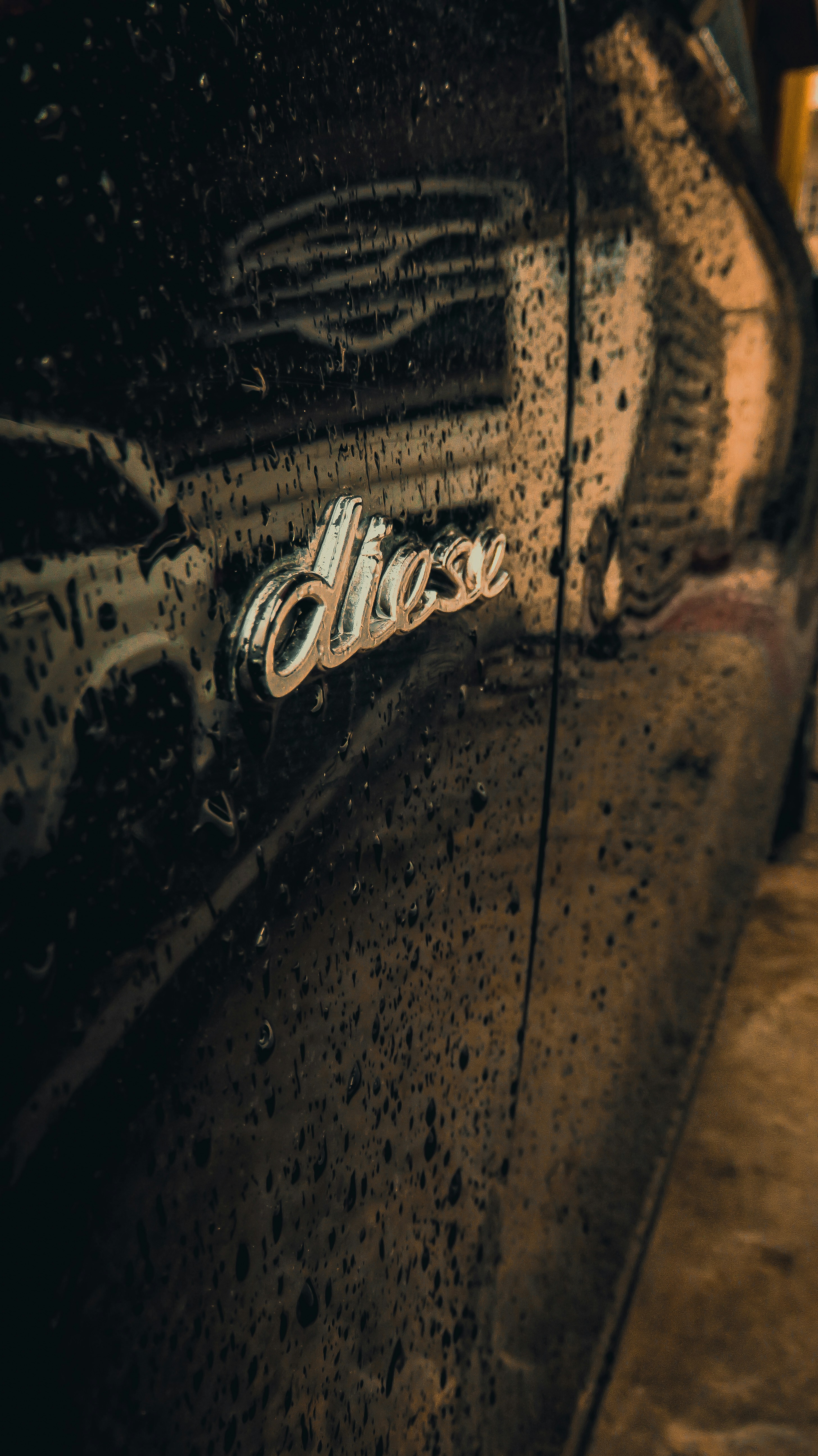 Chrome Badge in the Rain: A Diesel Emblem on a Midnight Vehicle