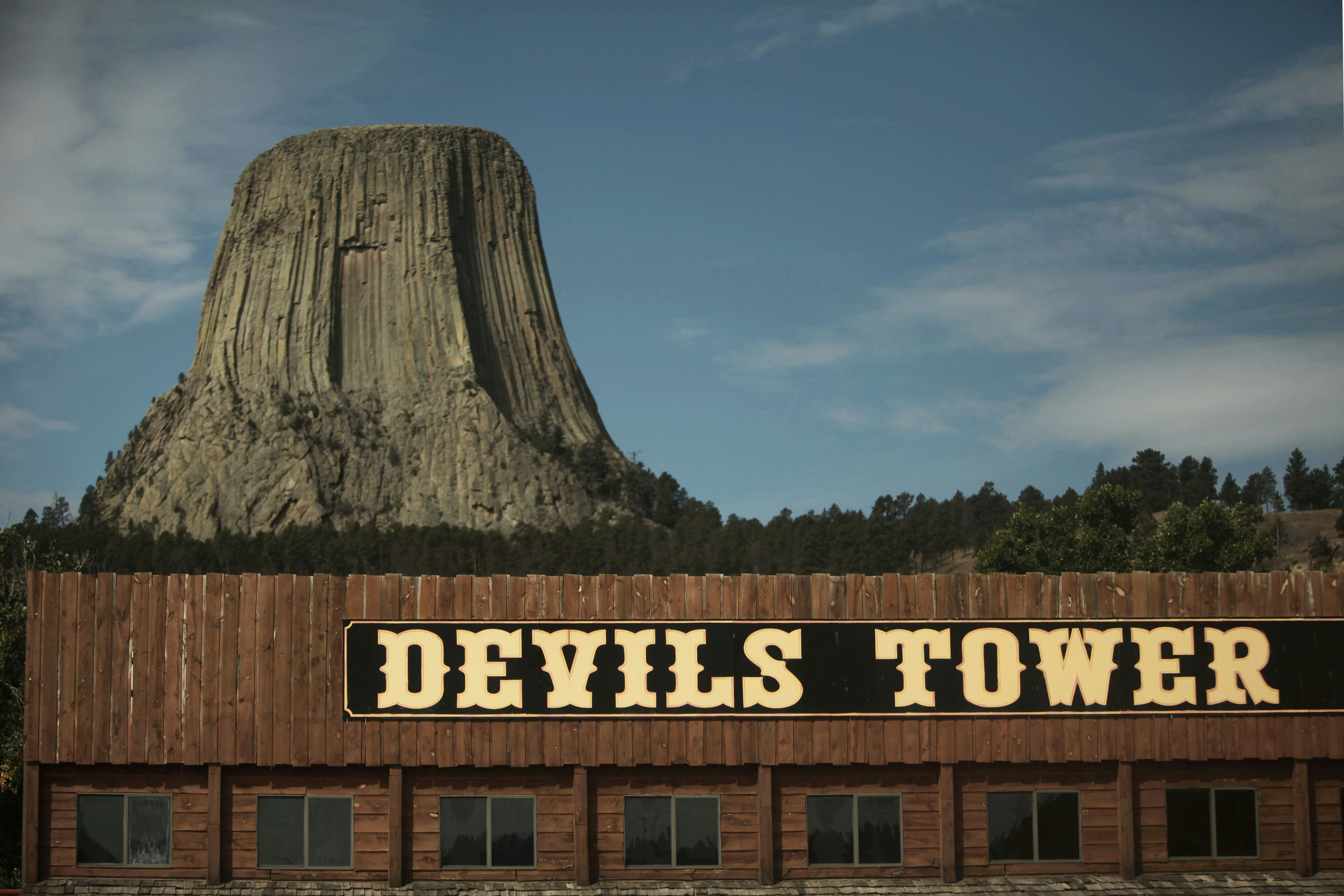 Prominent rock formation rising above a rustic wooden structure bearing the name 'Devils Tower.'