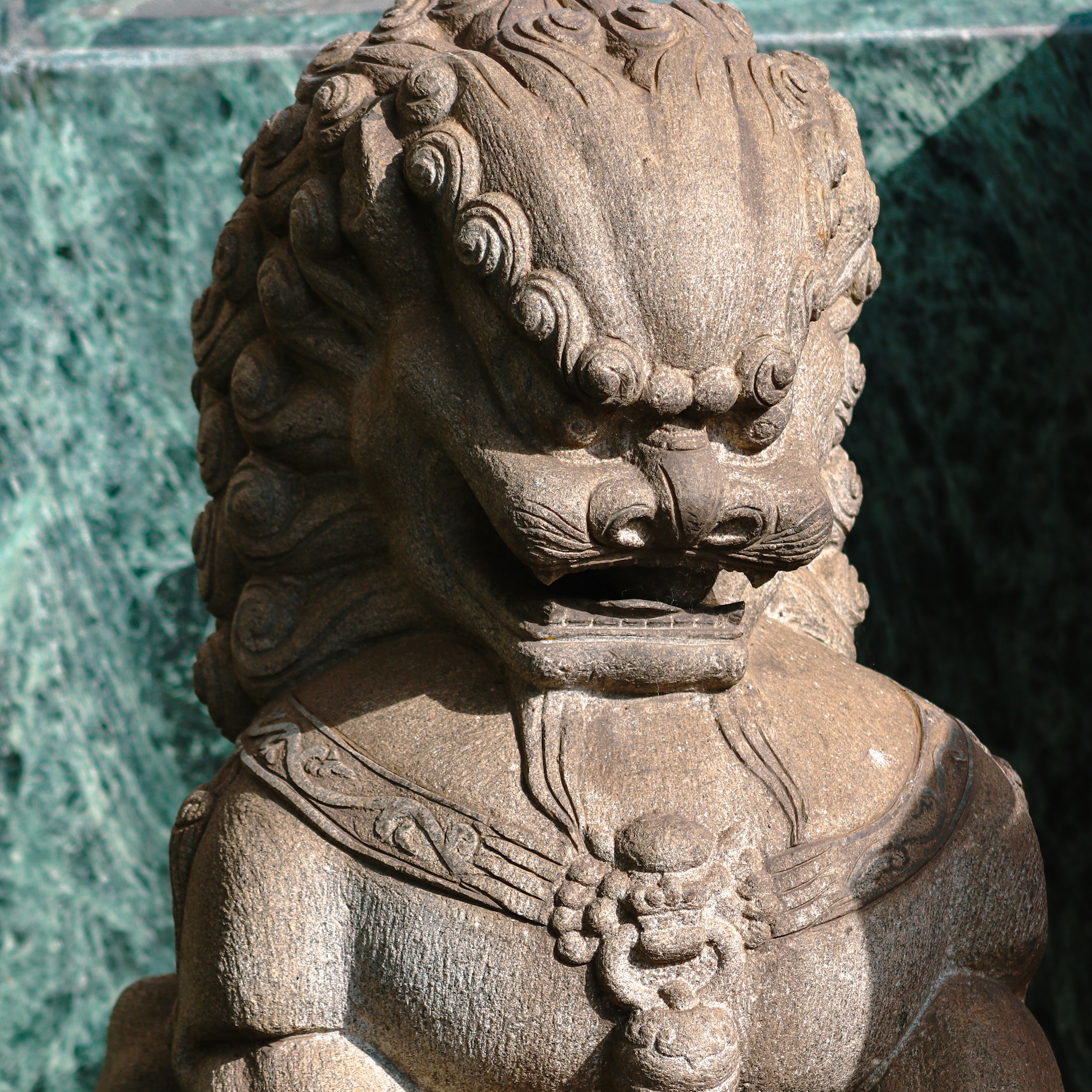 Intricately carved stone lion statue showcasing traditional artistry and cultural significance. The fierce expression and detailed features embody strength and protection.