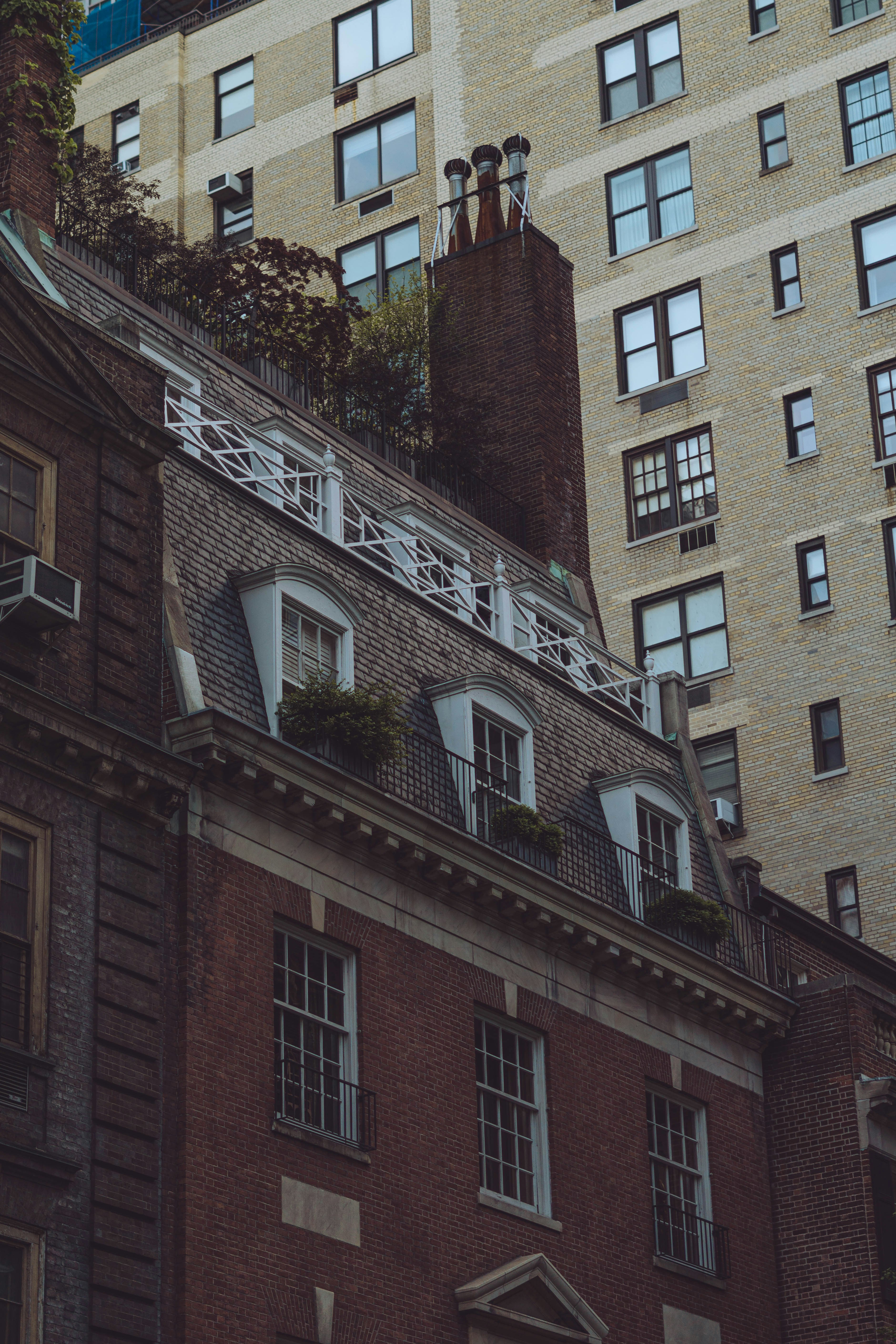 Historic brick building with intricate rooftop details contrasts with modern high-rise structures in an urban setting.
